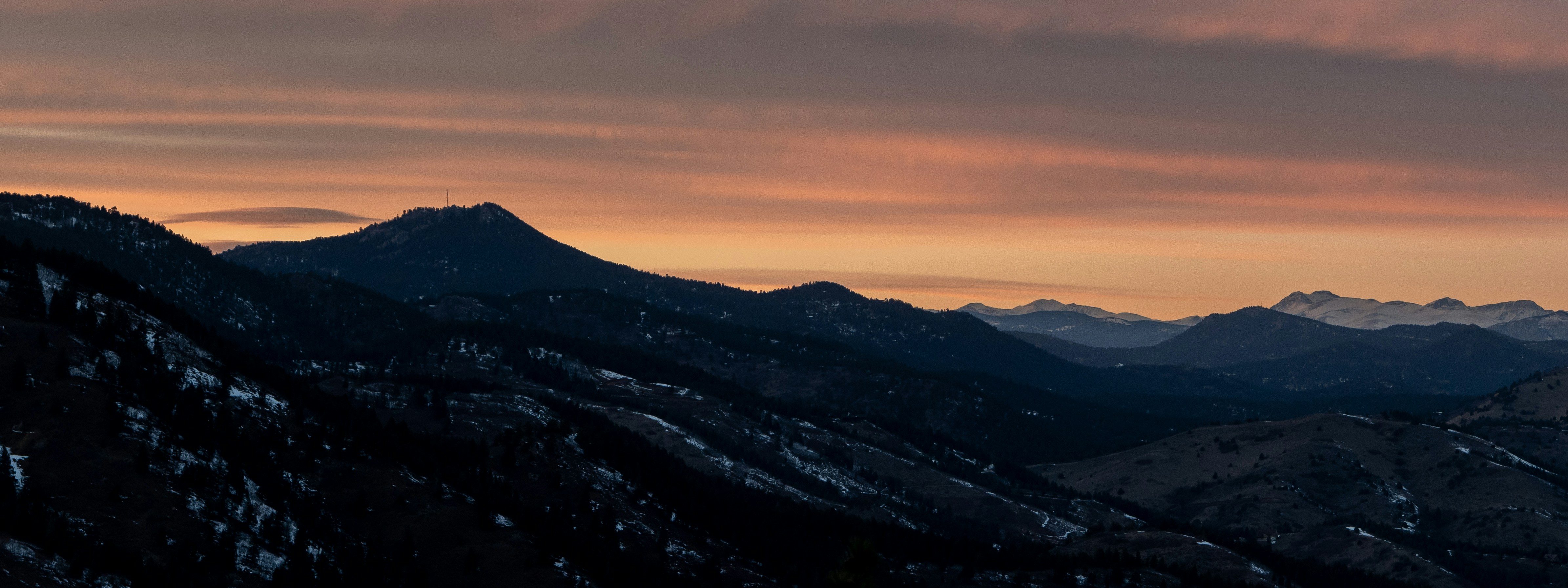 Snow-capped mountain range under a soft twilight sky, showcasing the transition from day to night.