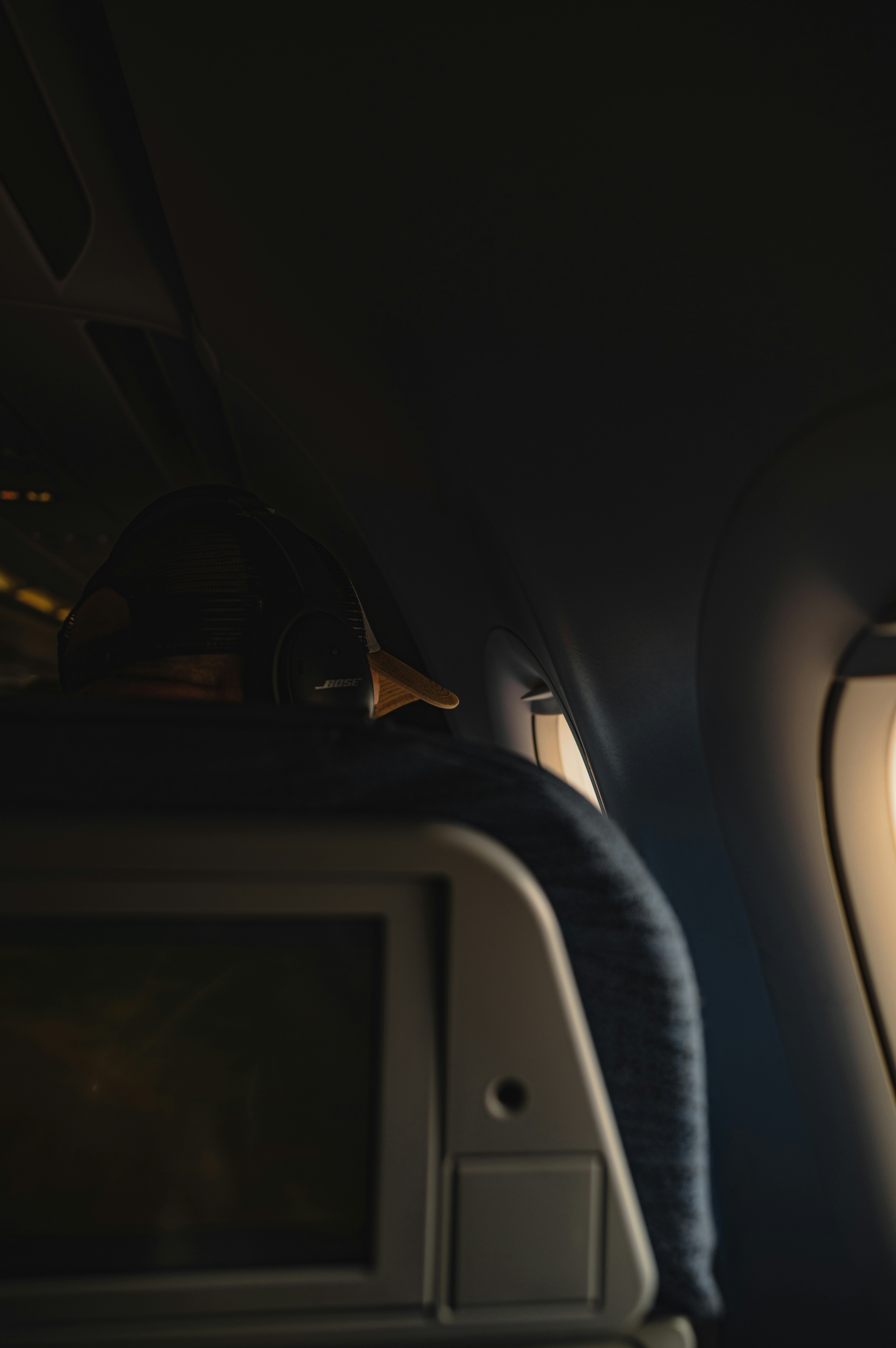 Seatback Reverie: Headphones Rest in a Dim Airplane Cabin with Window Light