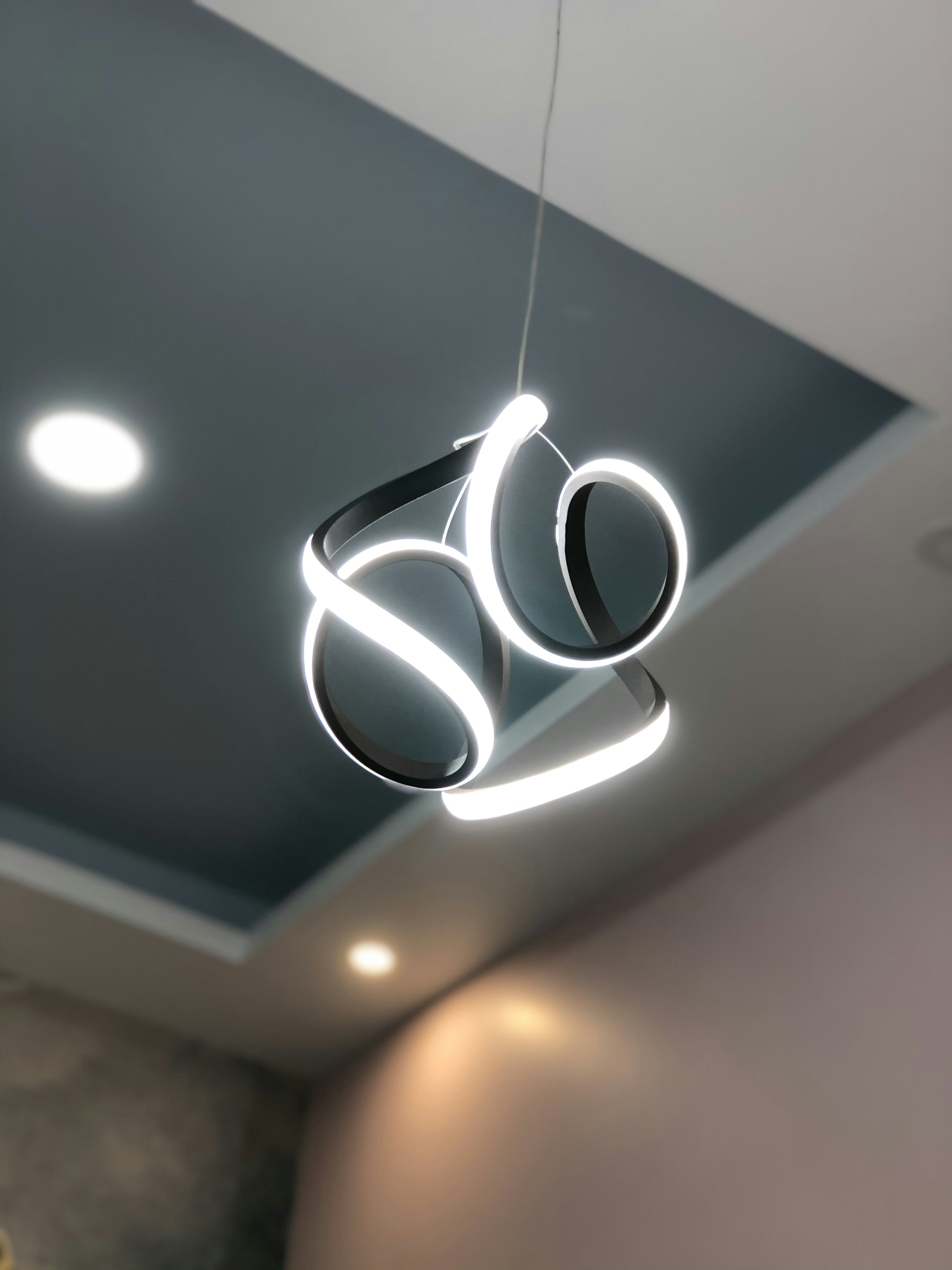 Sleek, abstract light fixture suspended from the ceiling, featuring flowing lines and a gentle glow that enhances the interior ambiance.