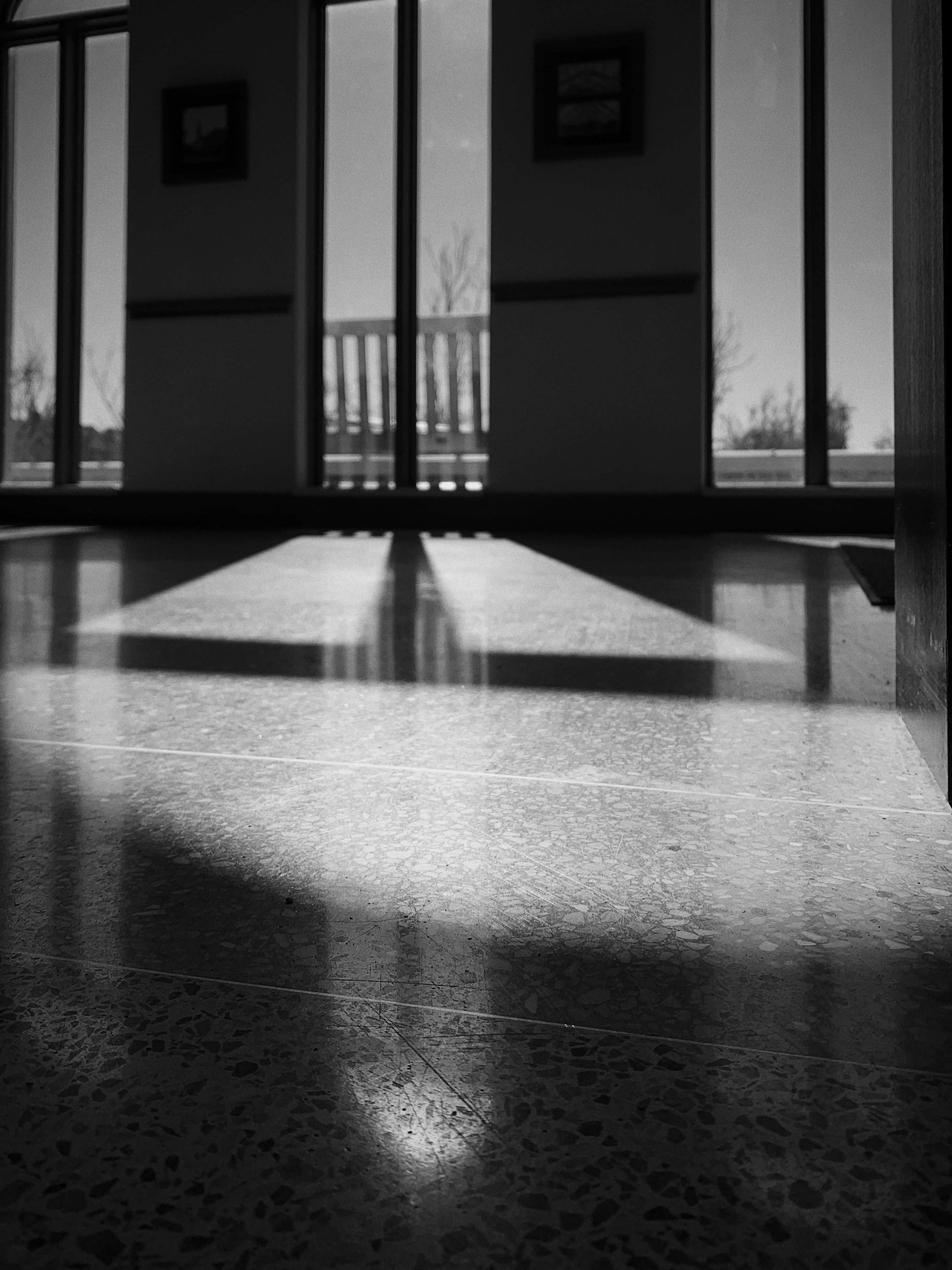 Monochrome interior scene showcasing elongated shadows cast by sunlight filtering through large windows.