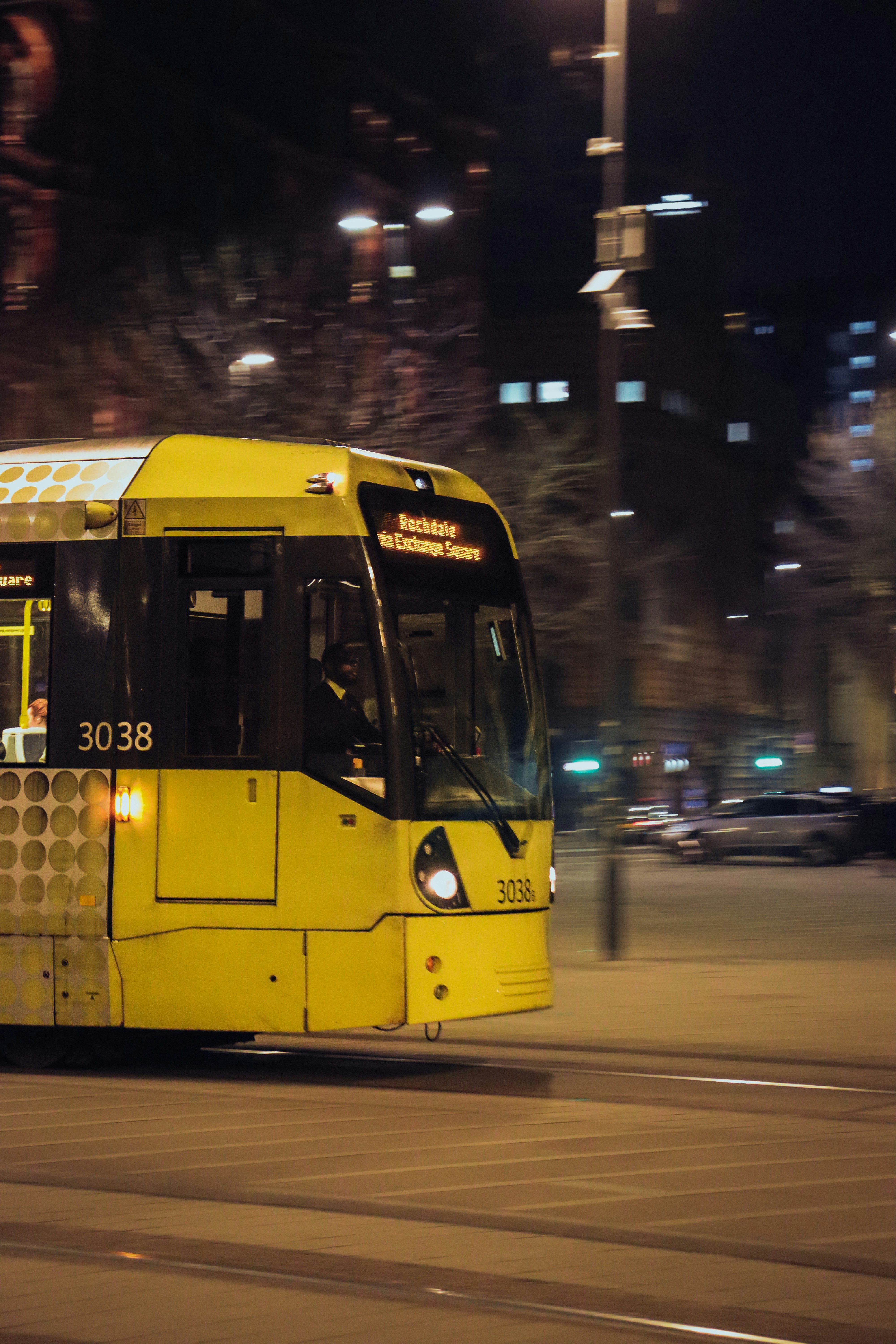 a yellow bus driving down a street at night