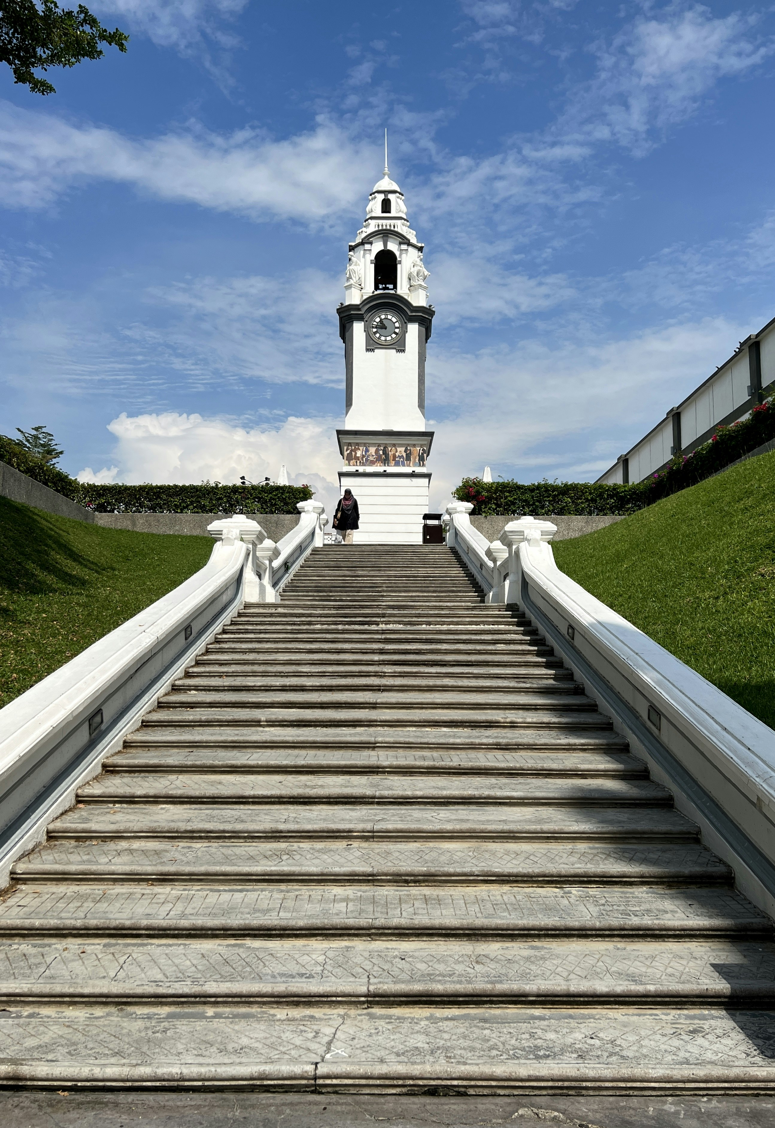 A very tall white clock tower sitting above a set of stairs photo ...