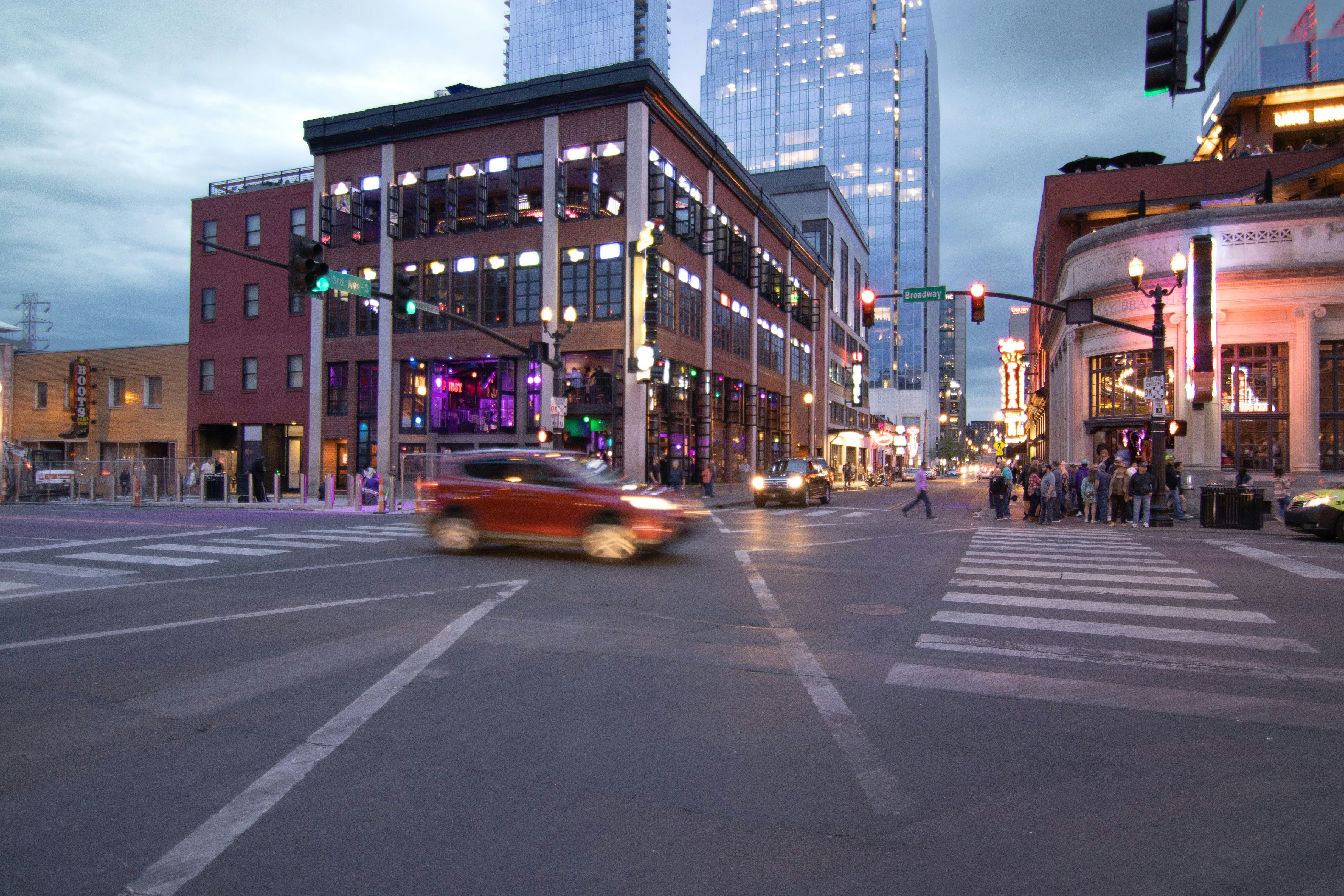 Twilight Crosswalk: Neon Facades and a Streaking Red Car
