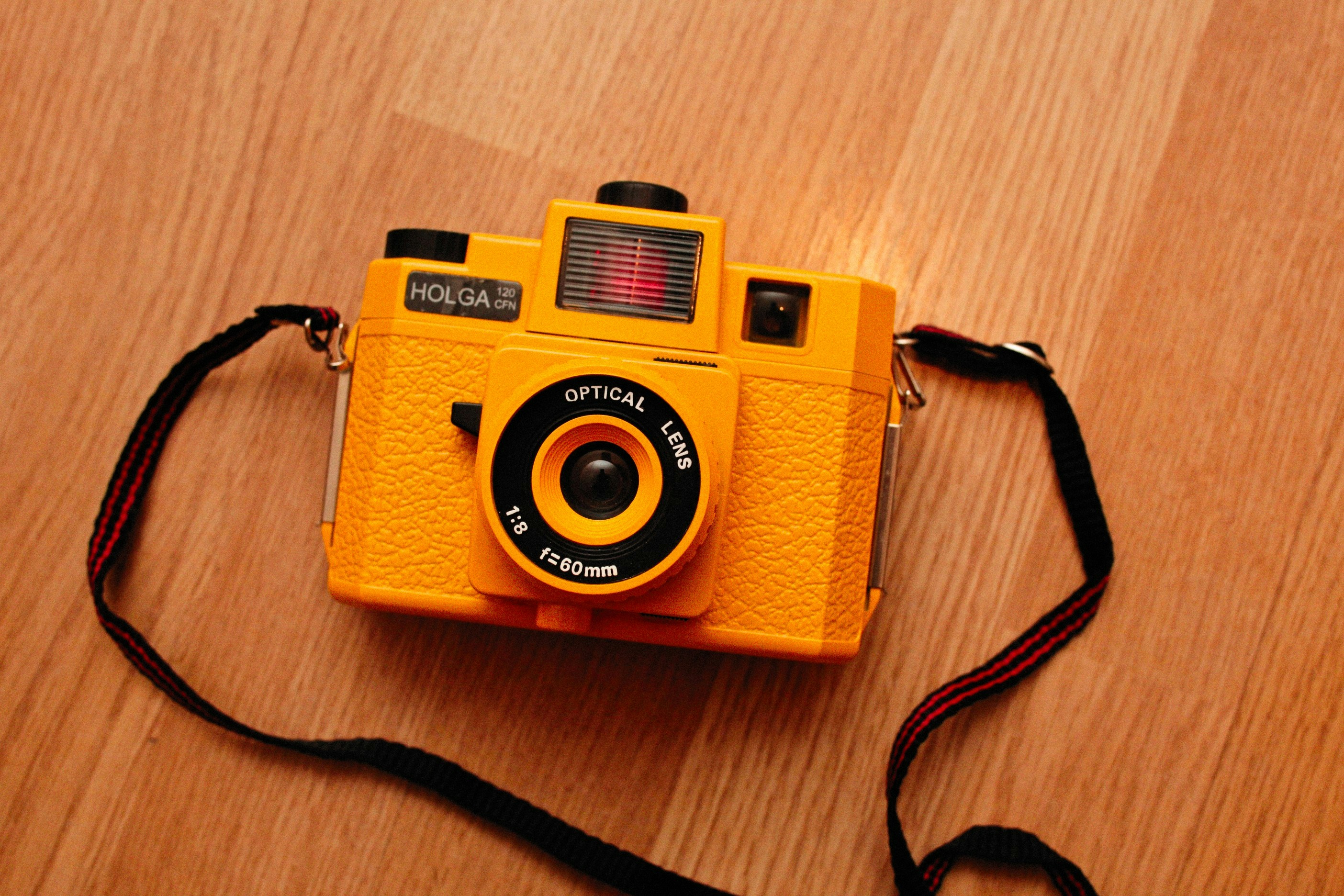 Amber Miniature: A Yellow Holga-style Camera Resting on Warm Wood