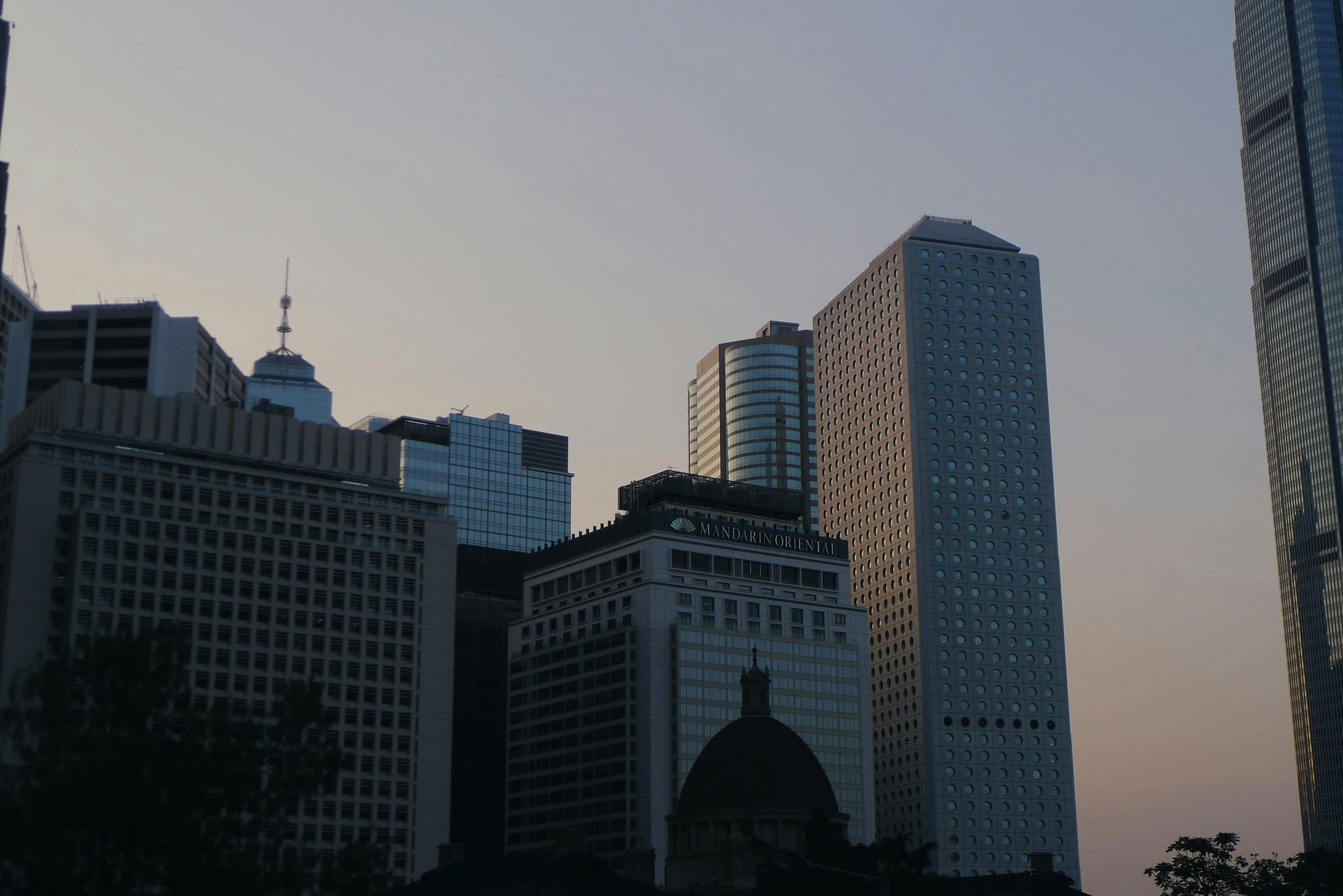 Skyline of modern skyscrapers silhouetted against a soft twilight sky, showcasing architectural diversity.
