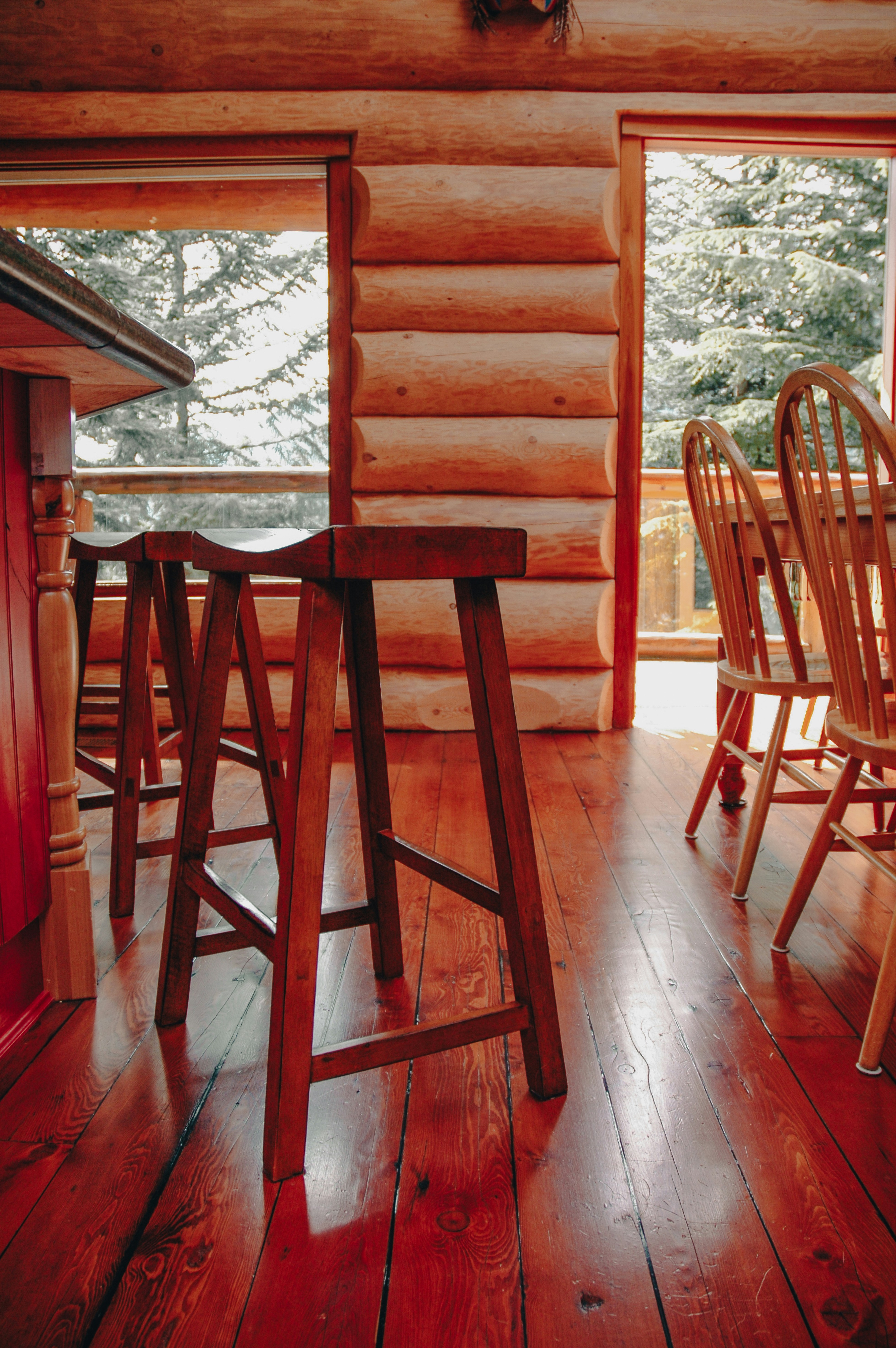 Wooden bar stools positioned in a sunlit log cabin, showcasing the warmth of natural materials and inviting ambiance.