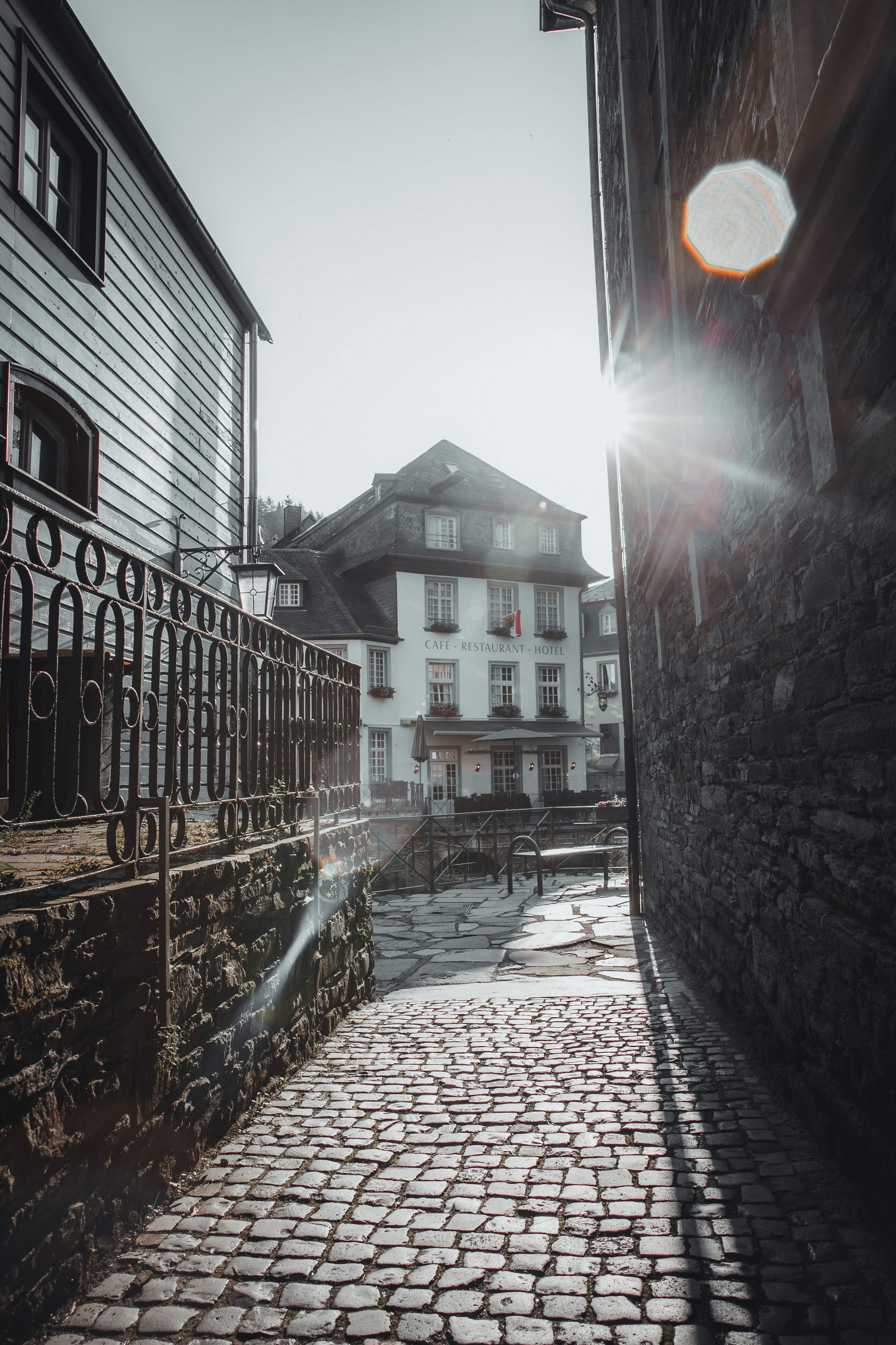 Sunlit Cobblestone Corridor Framing a Cozy European Café
