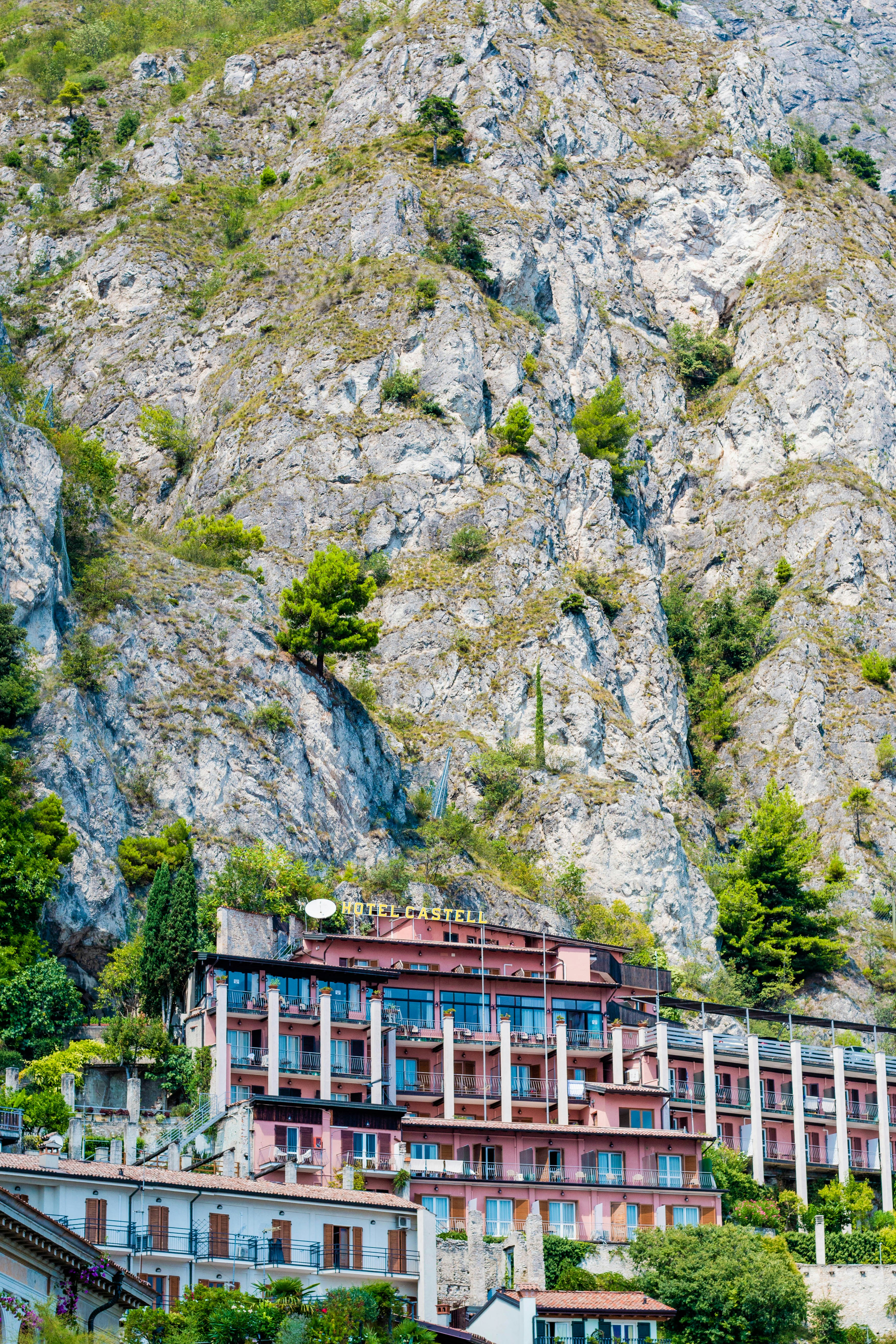 Hotel Castell nestled against a rocky cliffside, surrounded by lush greenery and towering mountains.