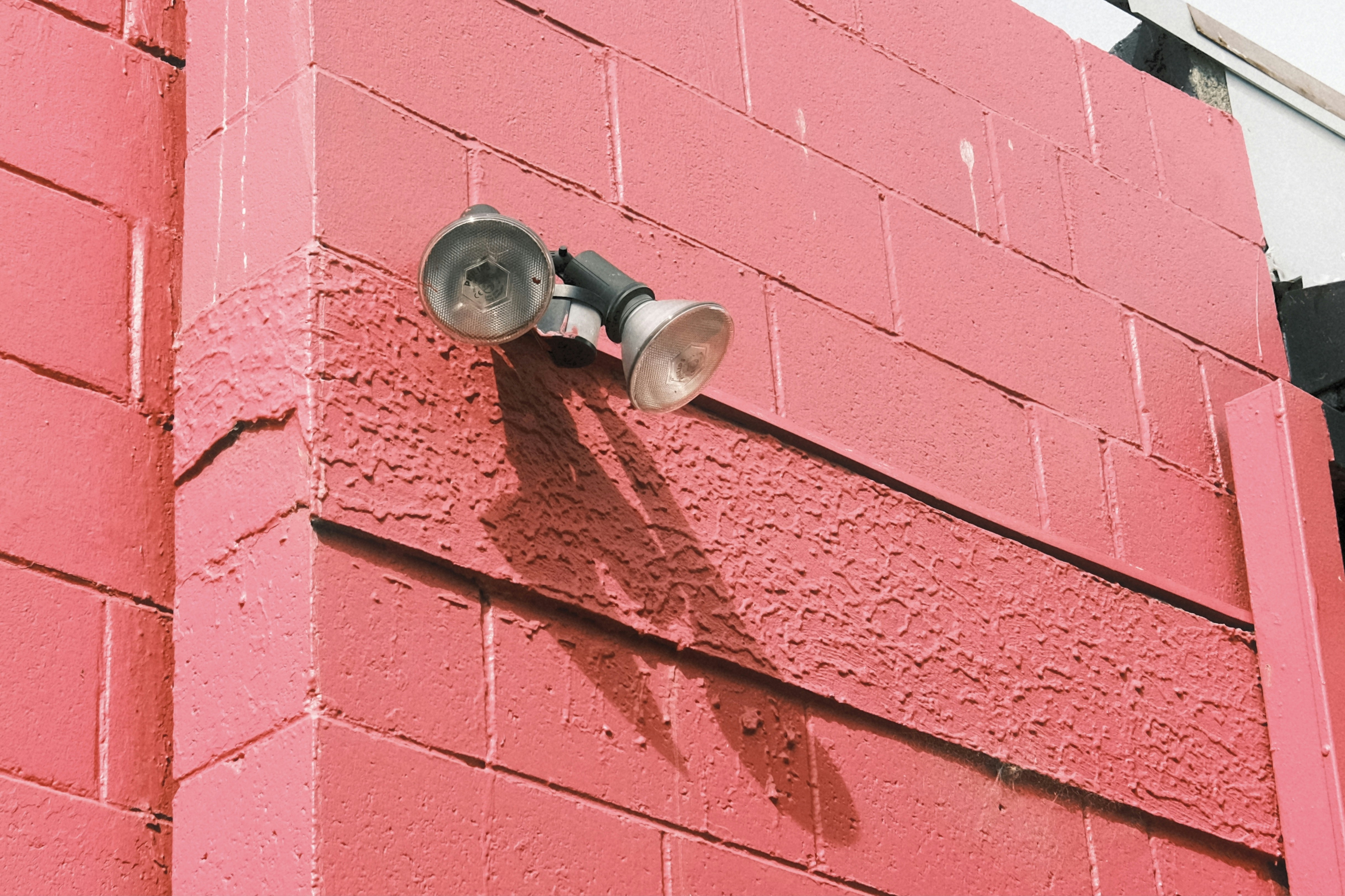 Dual Floodlights on a Brick-Red Wall: A Minimal Shadow Play