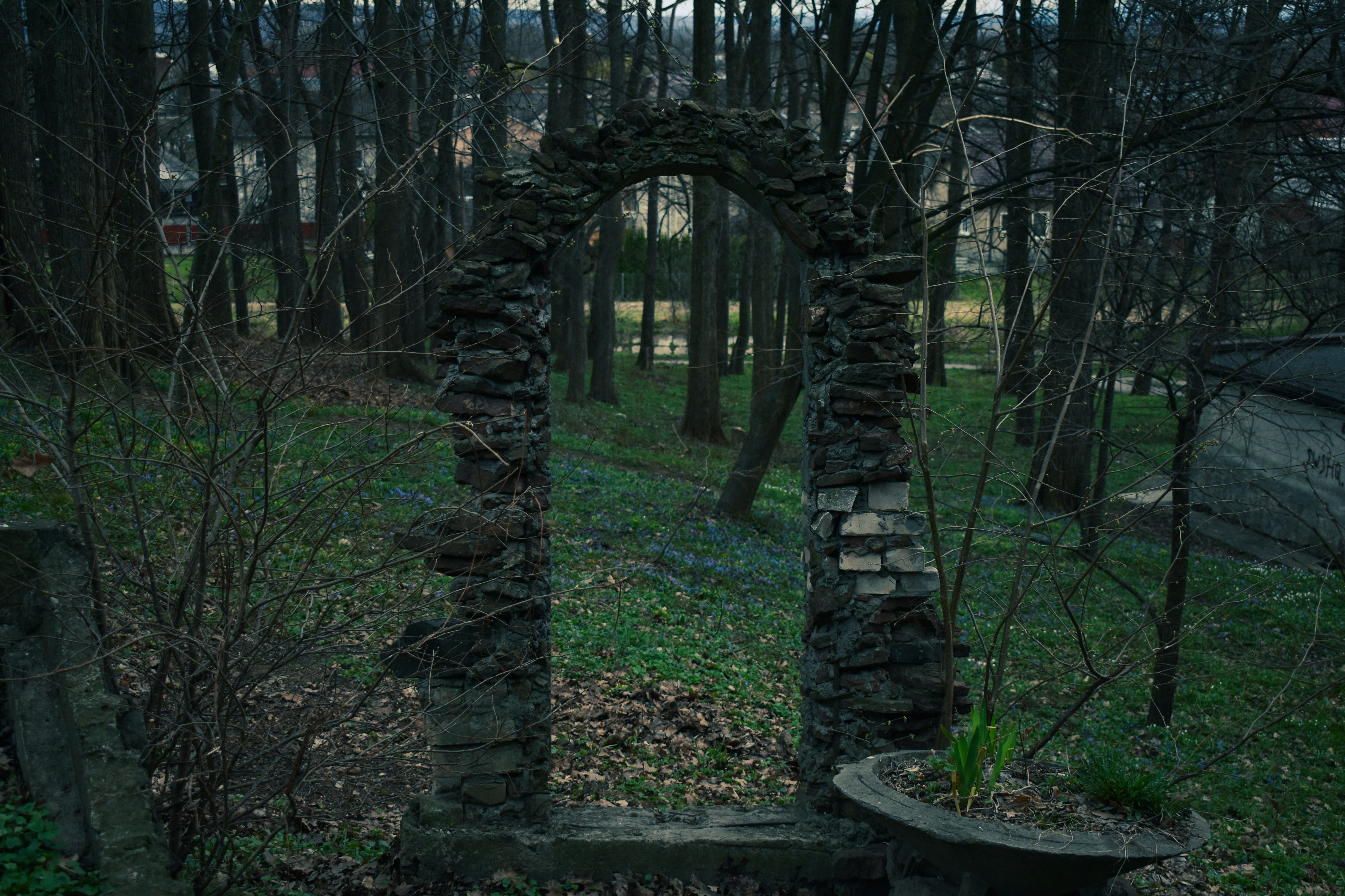 An ancient stone archway framed by a serene forest, hinting at the passage of time and nature's embrace.