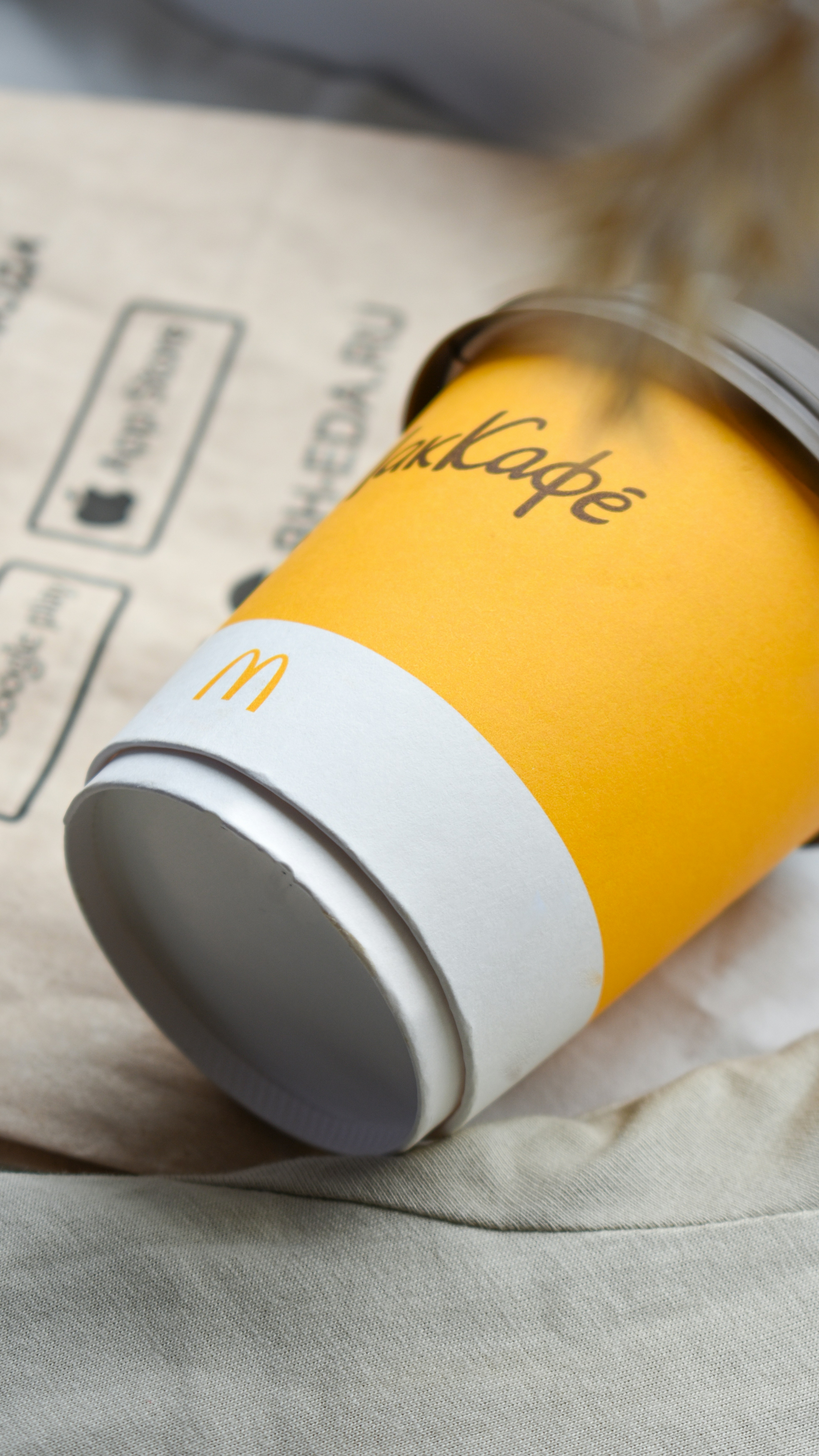 Tilted McCafé Cup on Cream Linen: Quiet Morning Glow