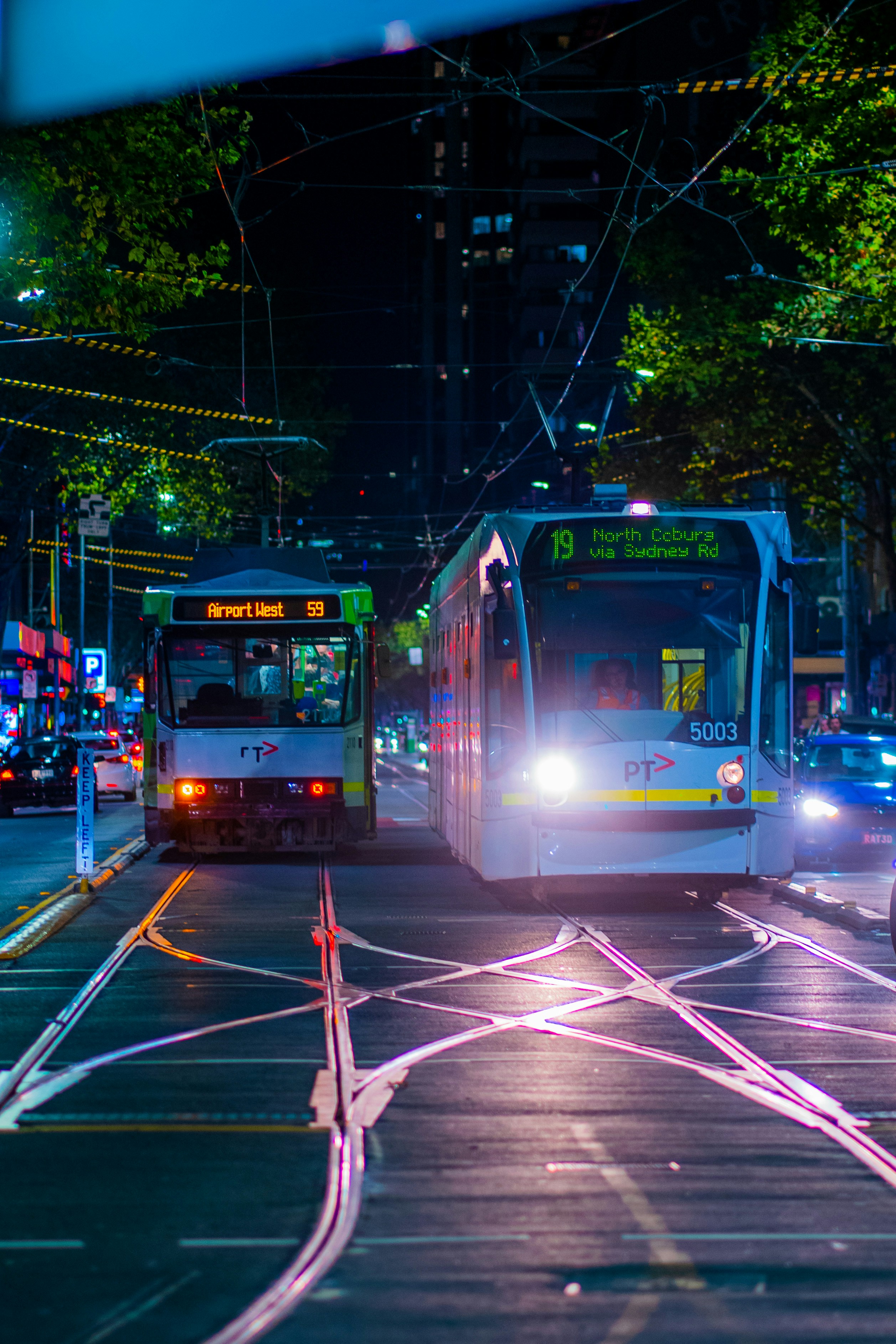 A couple of buses driving down a street at night photo – Free Elizabeth ...