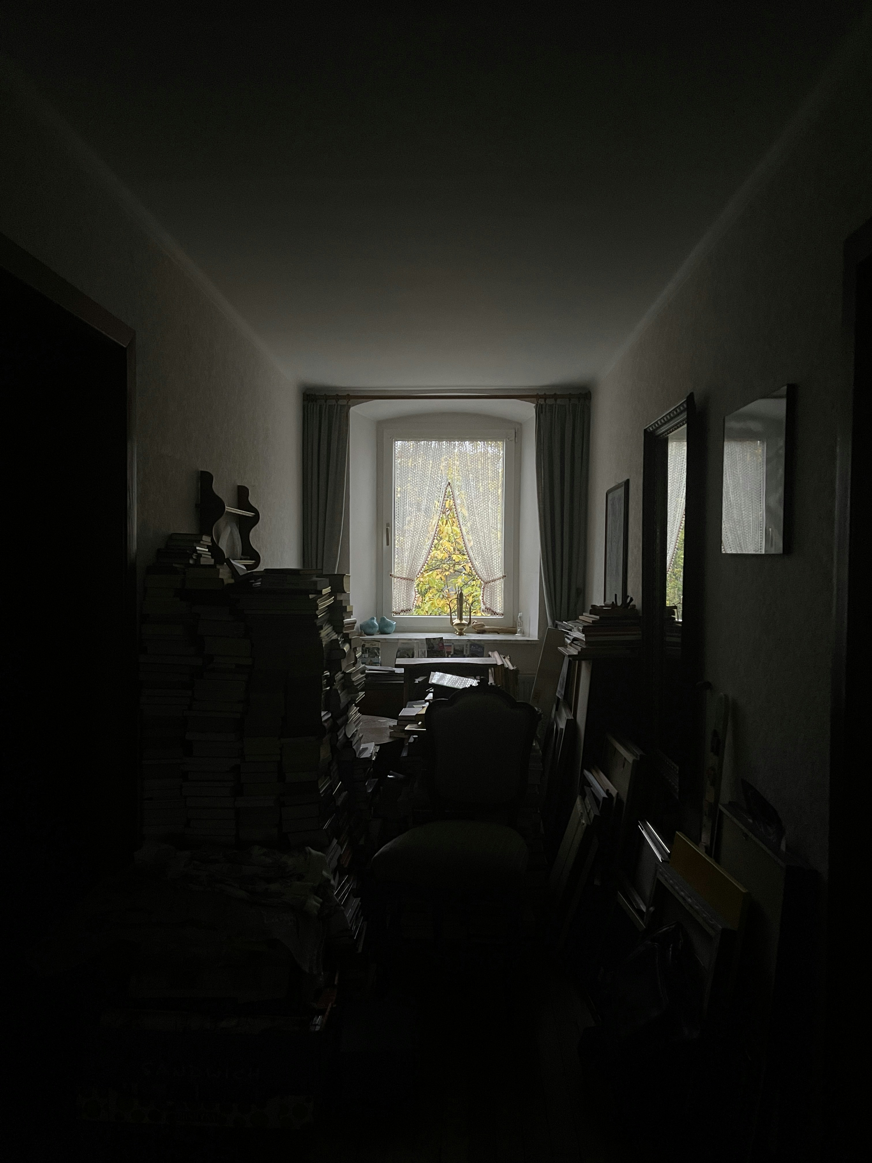a dark room with a chair and a window