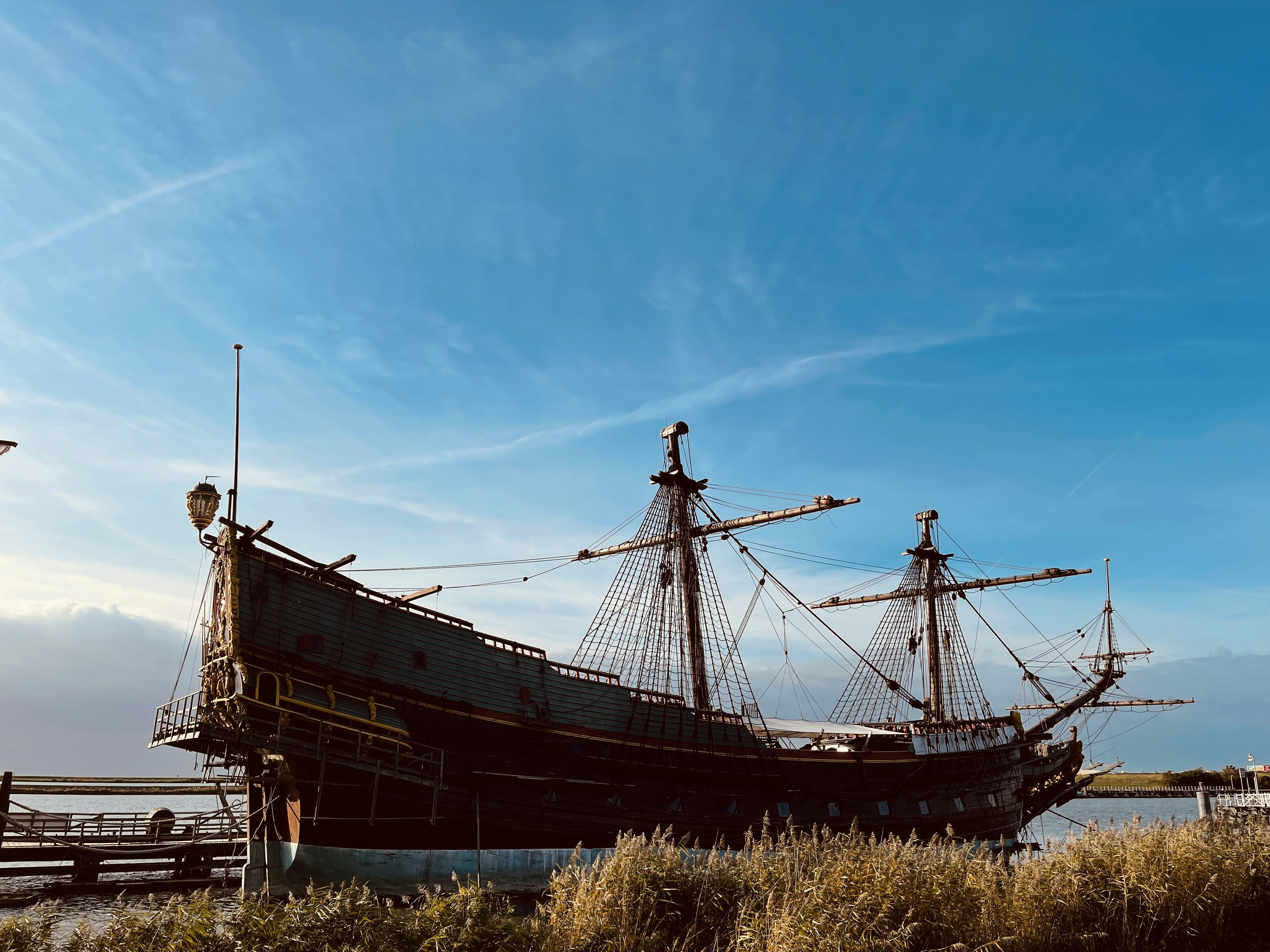 Timber-Galleon at the Harbor: Mast Prominence Under a Clear Blue Sky