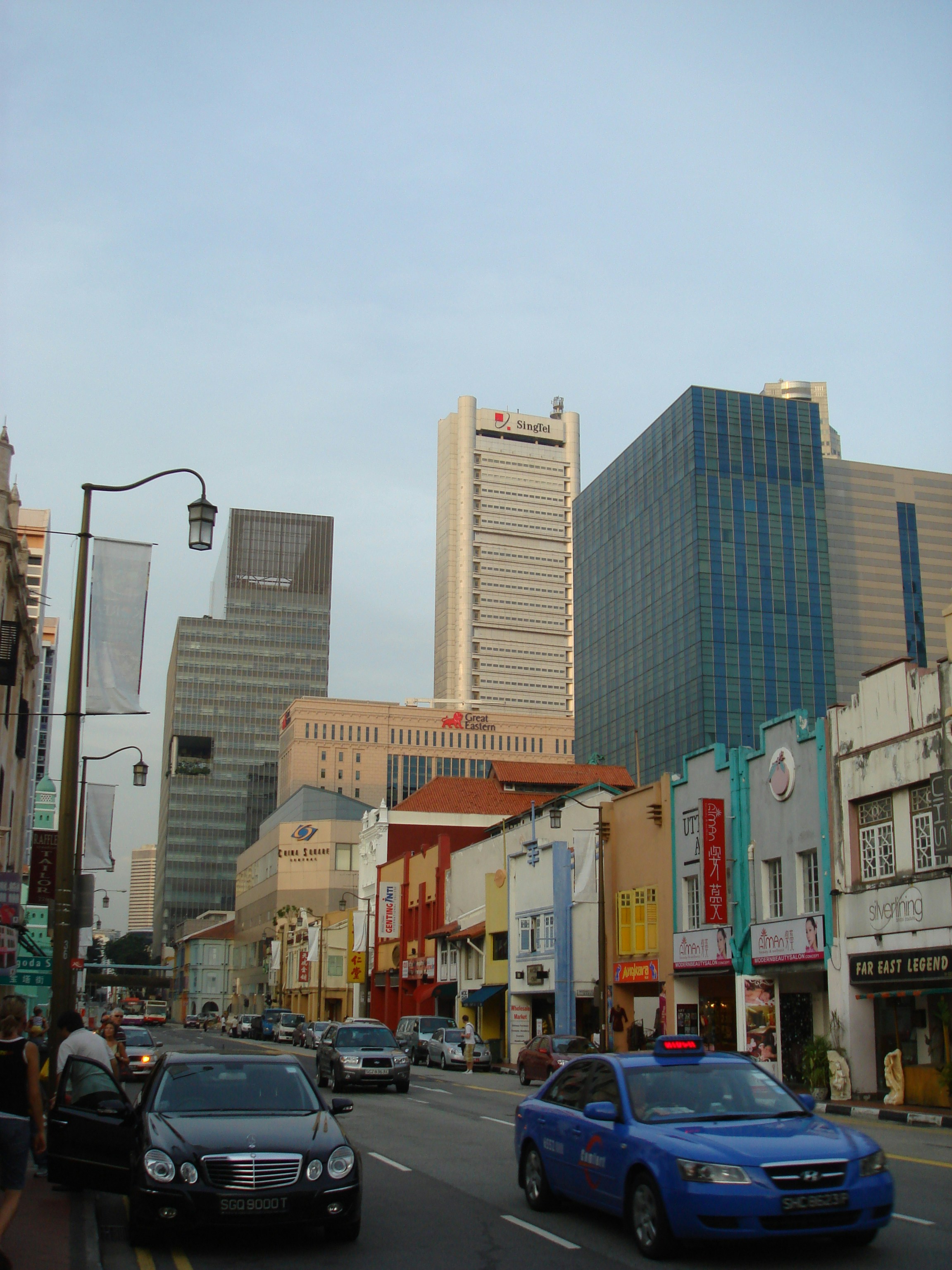 Vibrant street scene showcasing a blend of modern skyscrapers and colorful heritage buildings. The bustling road captures the essence of urban life.