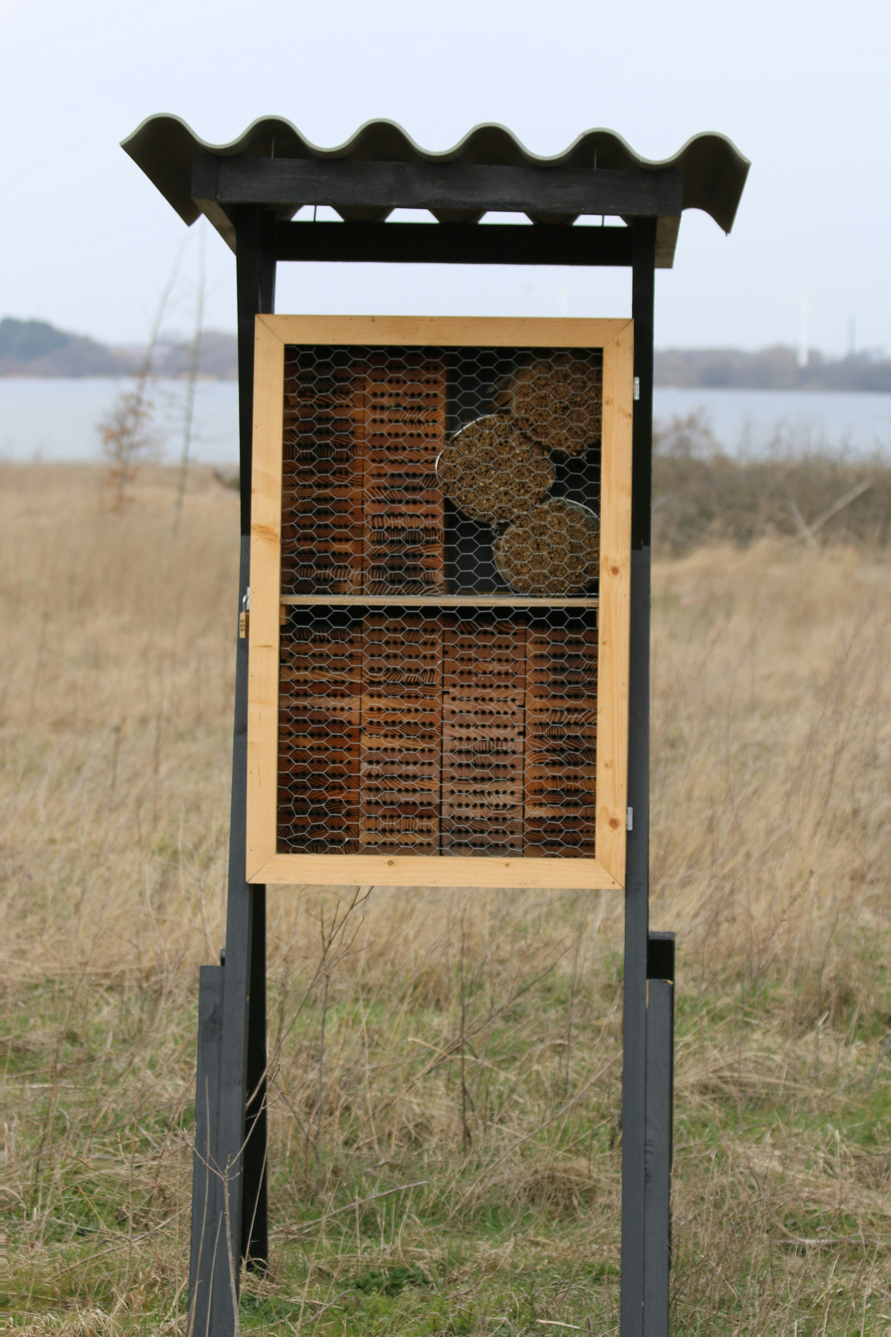 a bird feeder in a field next to a sign