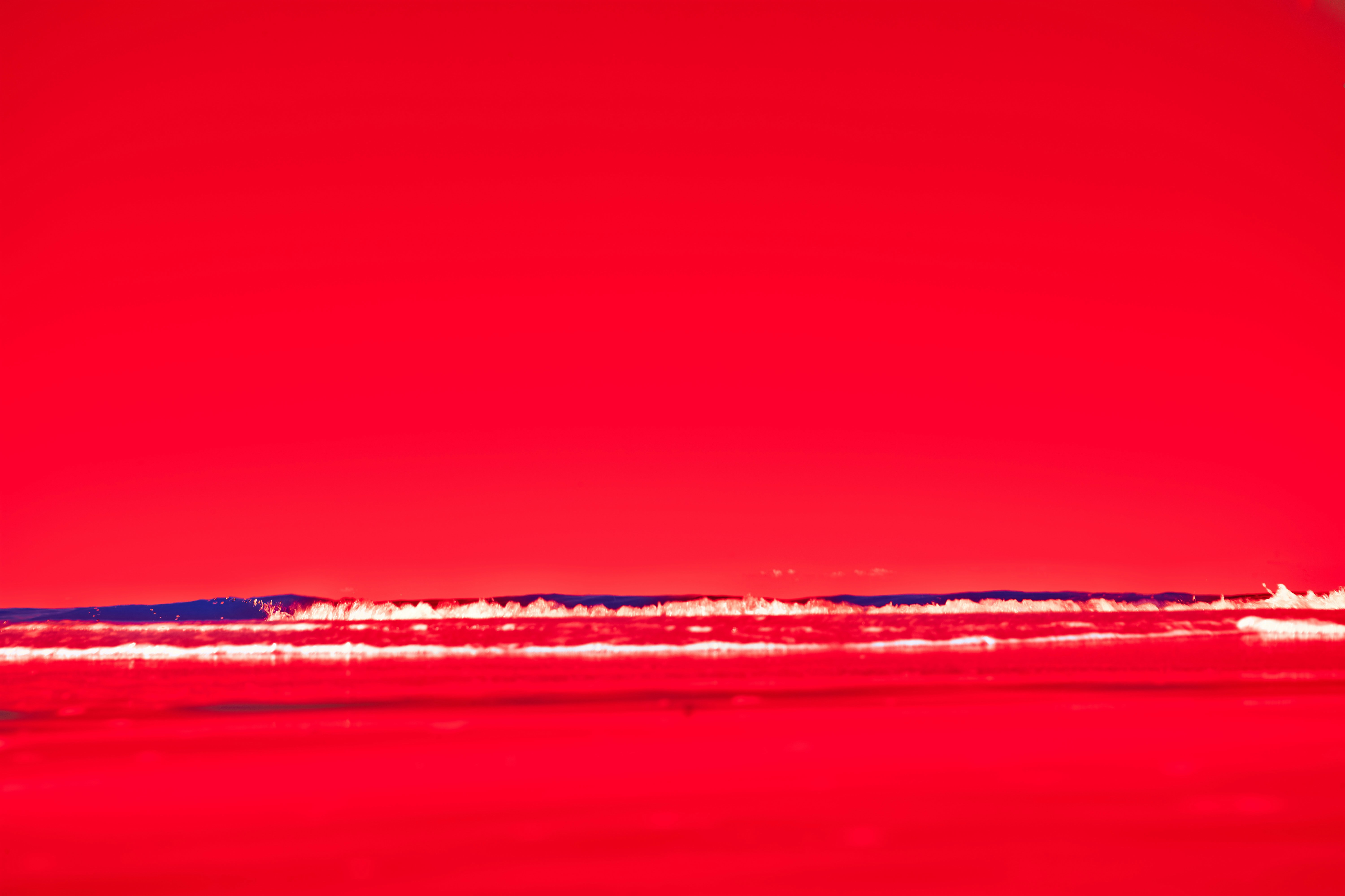 Une photo rouge d’une plage avec un bateau dans l’eau photo – Image ...