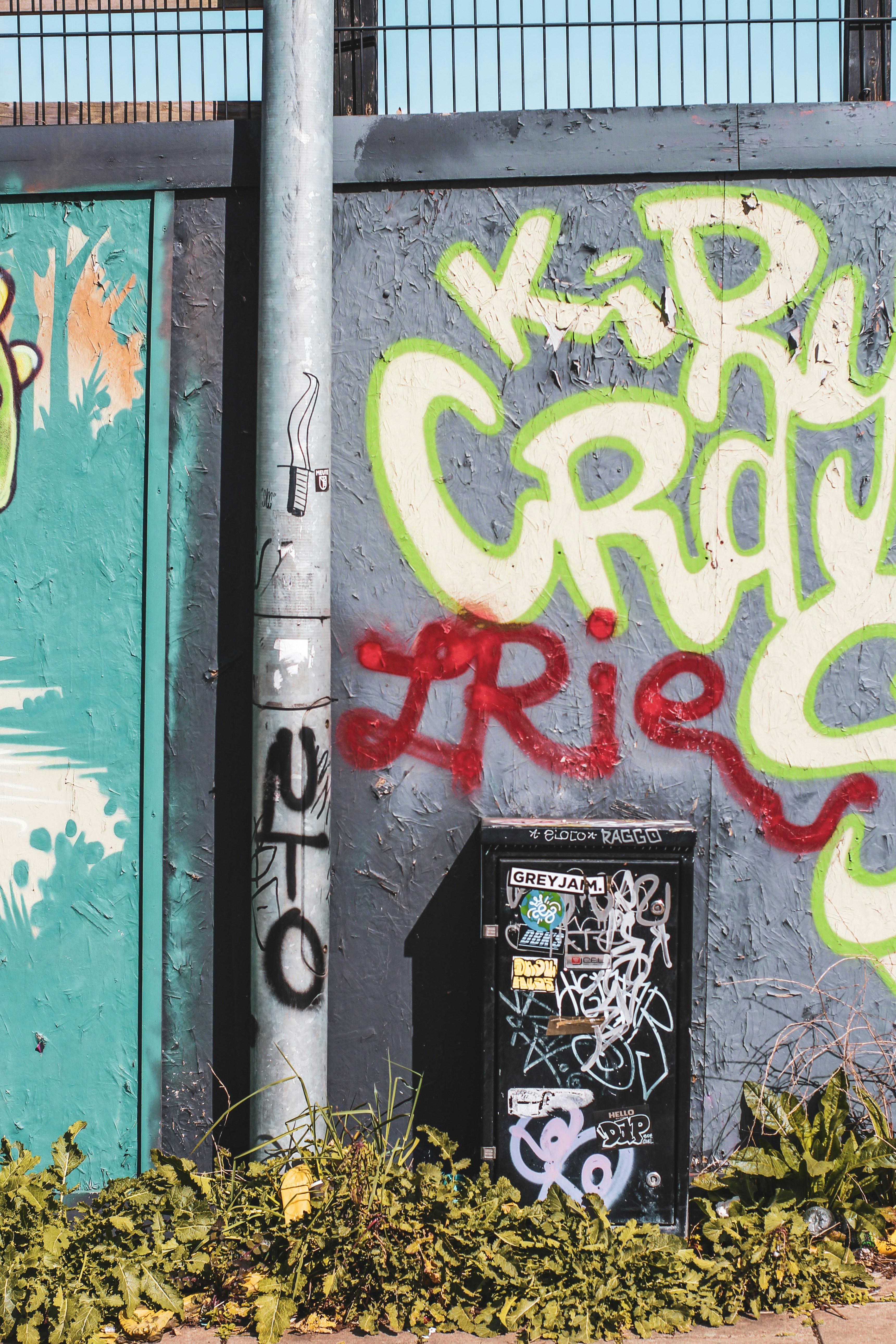 graffiti on the side of a building near a trash can