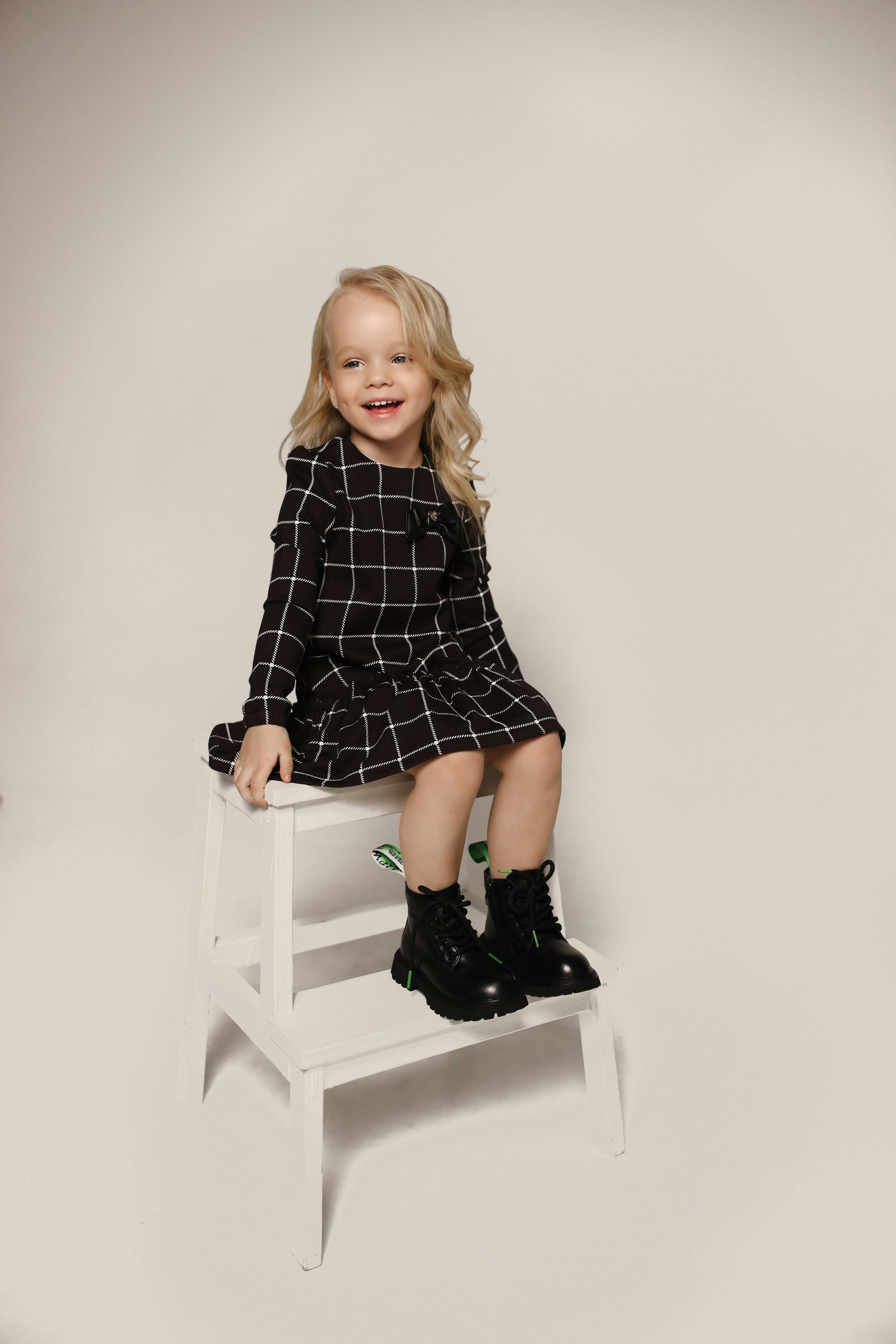 A little girl sitting on a white step stool photo – Free Grey Image on ...