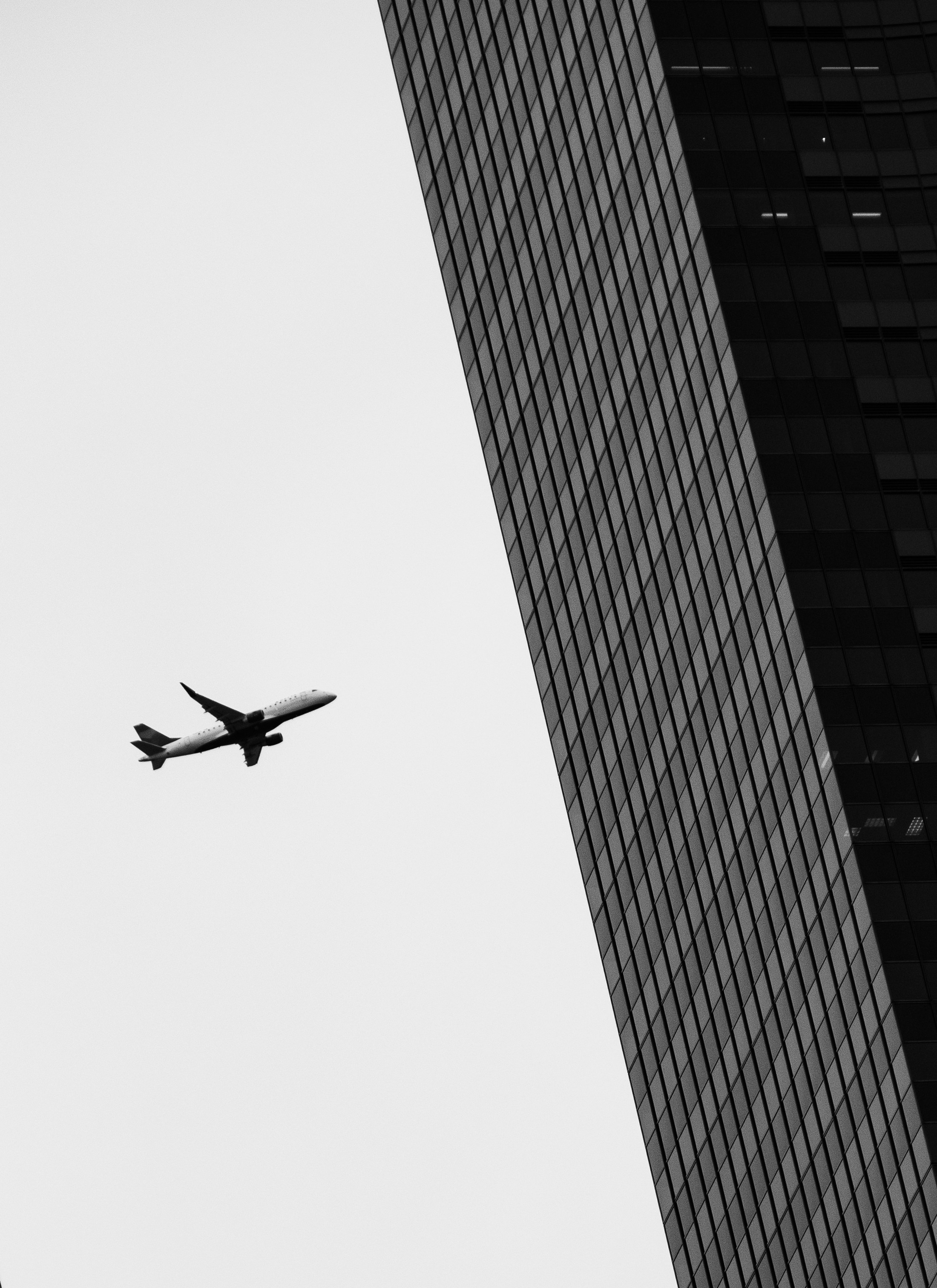 An airplane flying in the sky between two tall buildings photo – Free ...