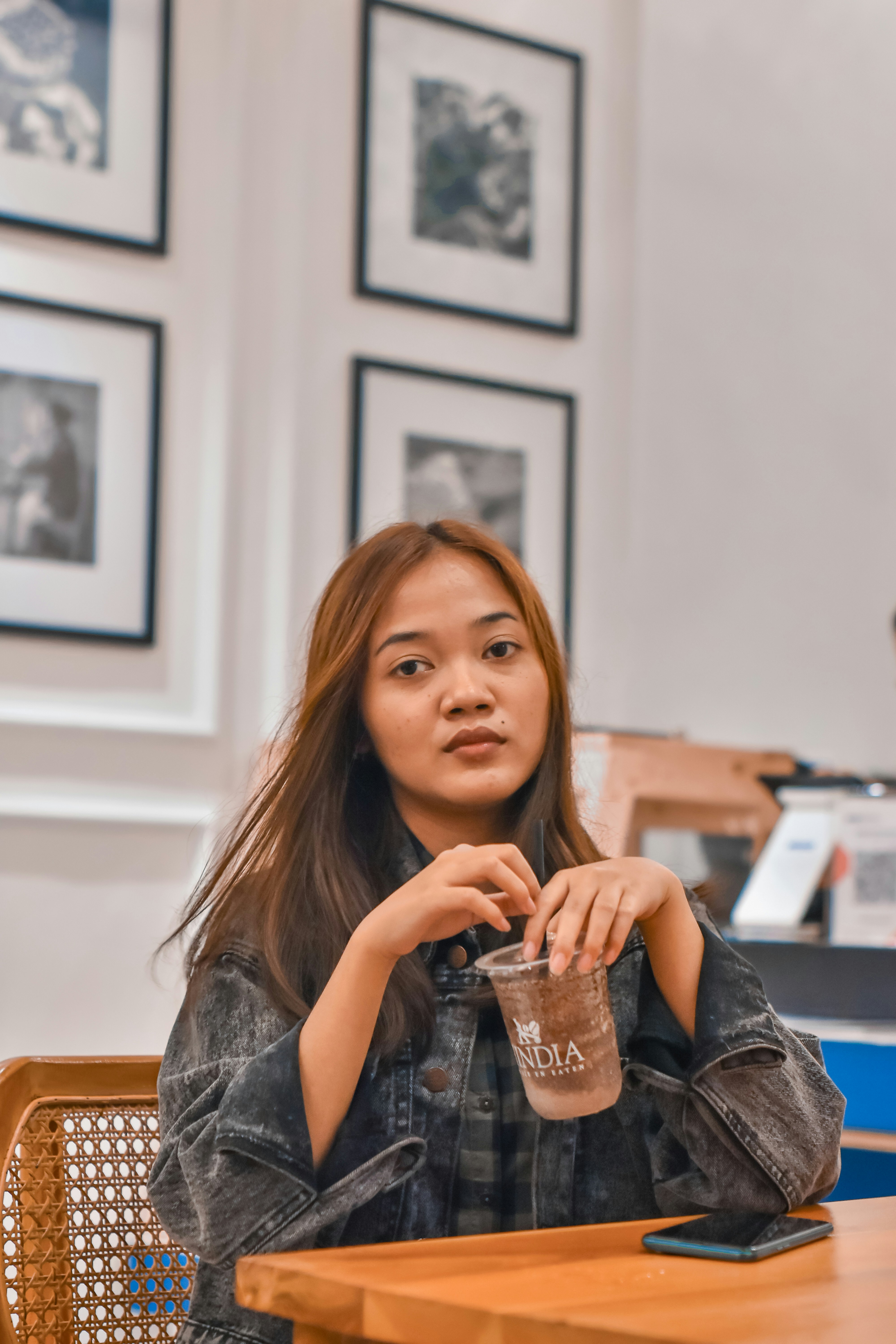 Foto Una mujer sentada en una mesa con un vaso en la mano – Imagen Gris gratis en Unsplash