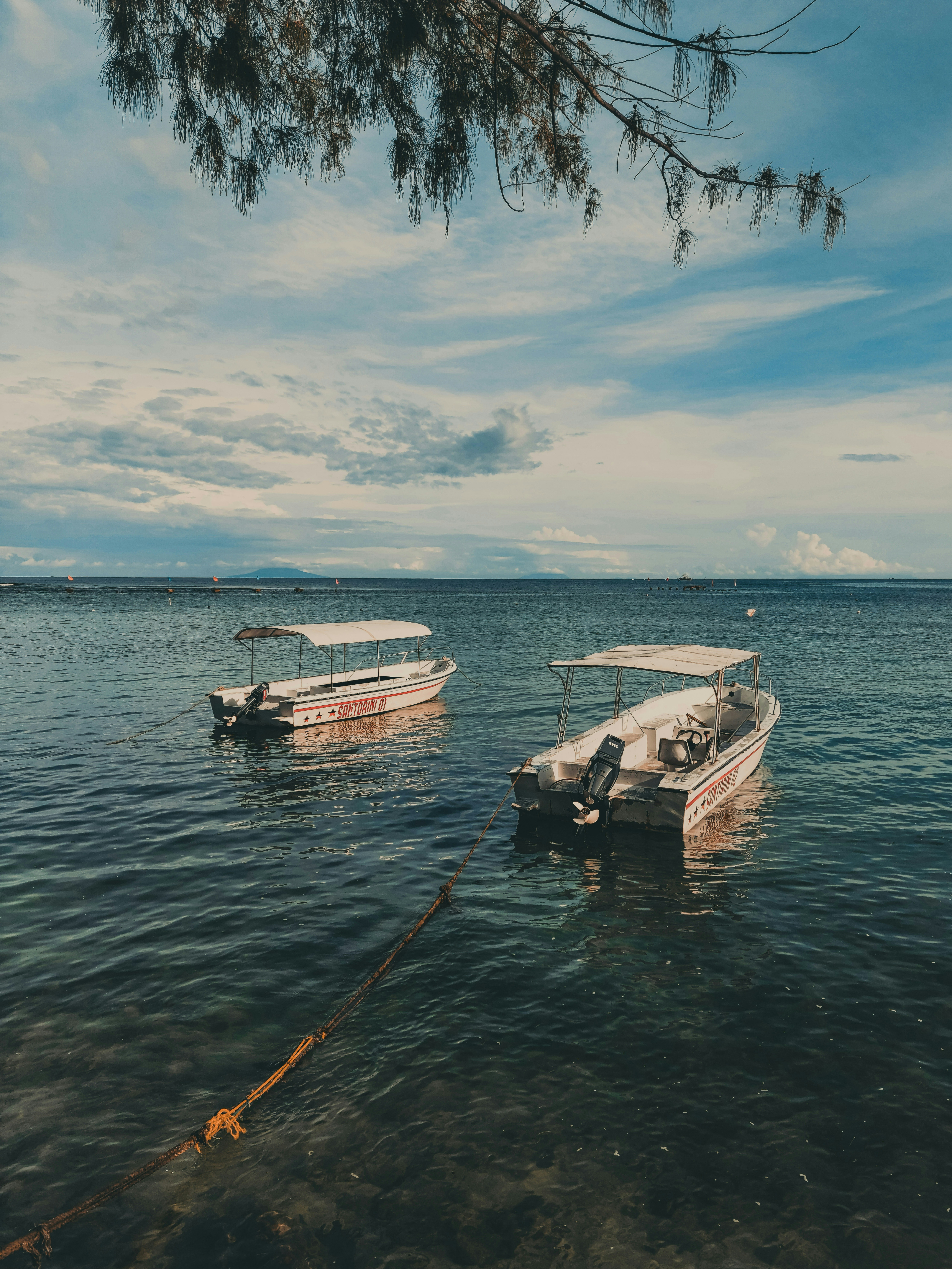 Un par de botes que están sentados en el agua foto – Imagen de Pantai ...