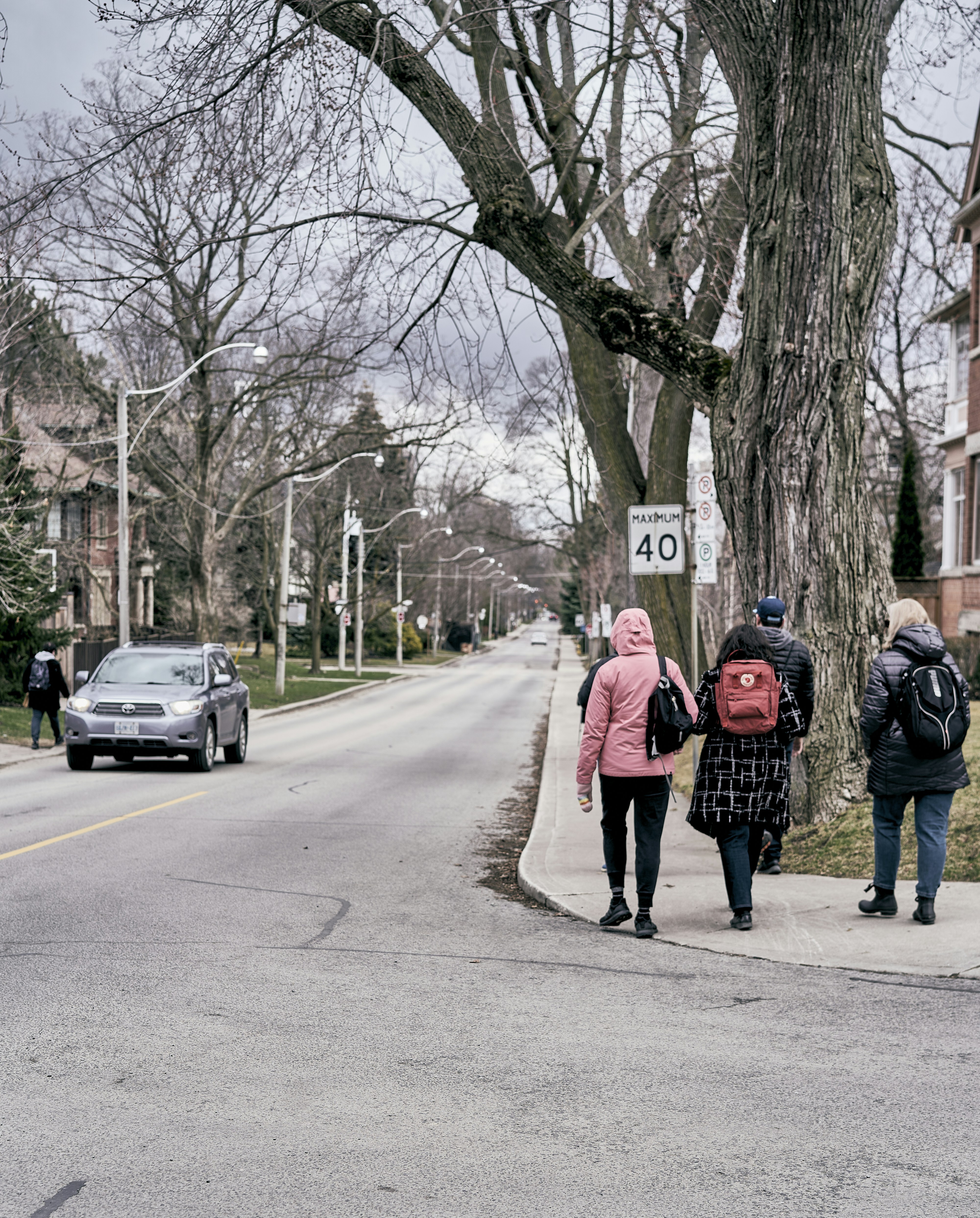 a group of people walking down a street next to a tree