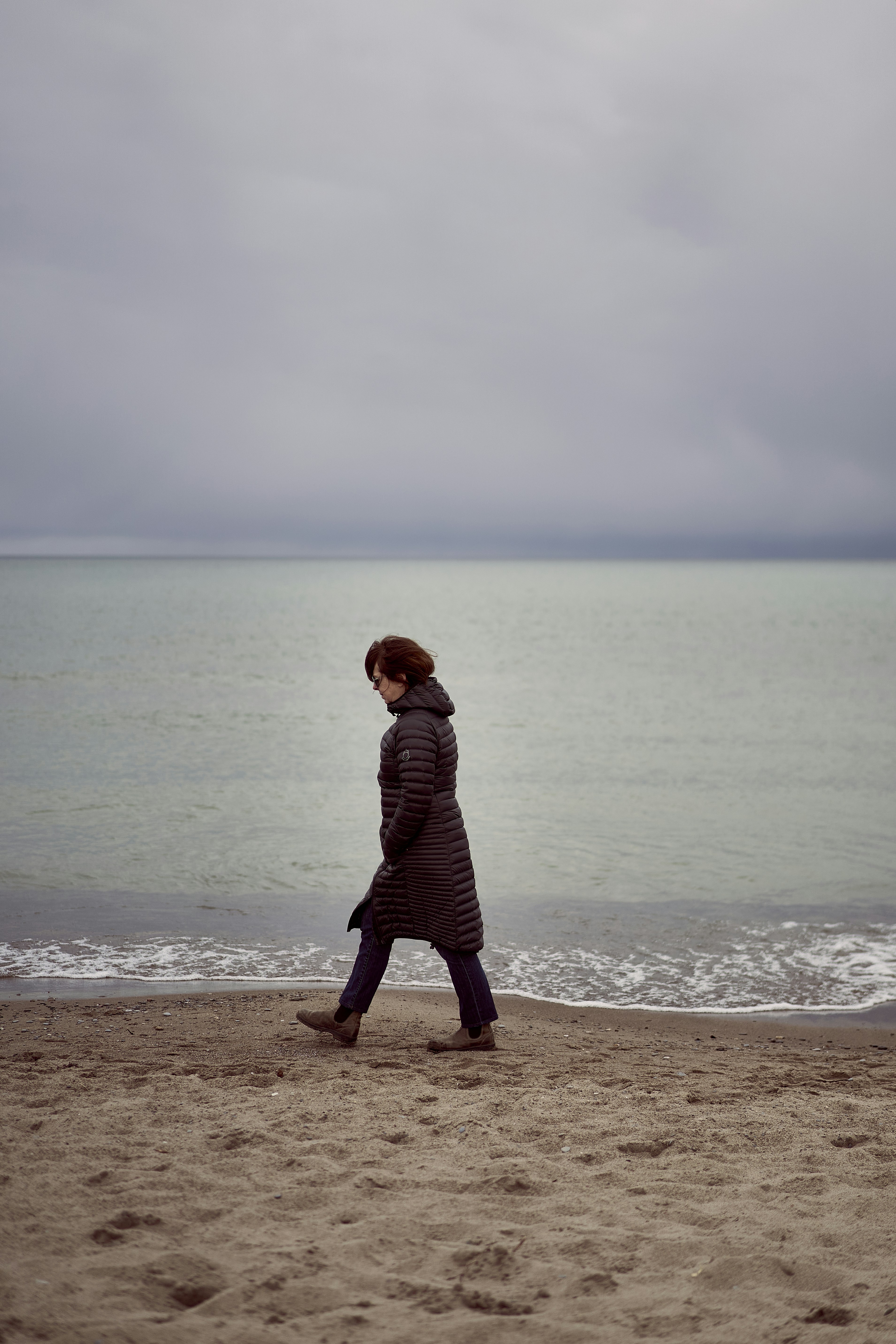 Solitary Walk on a Pale Shore under a Stoic Sky