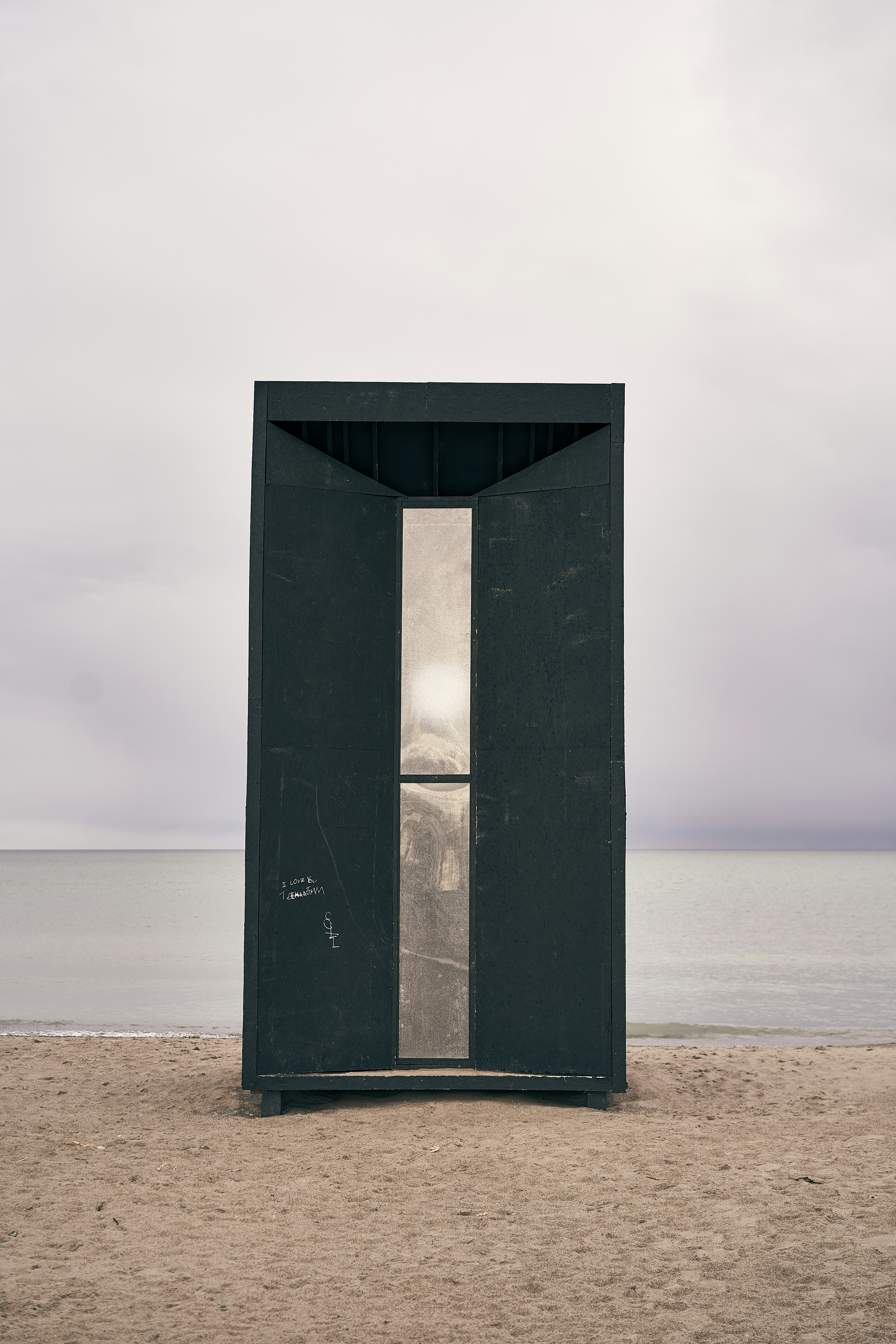 Foto Una letrina negra sentada en la cima de una playa de arena ...
