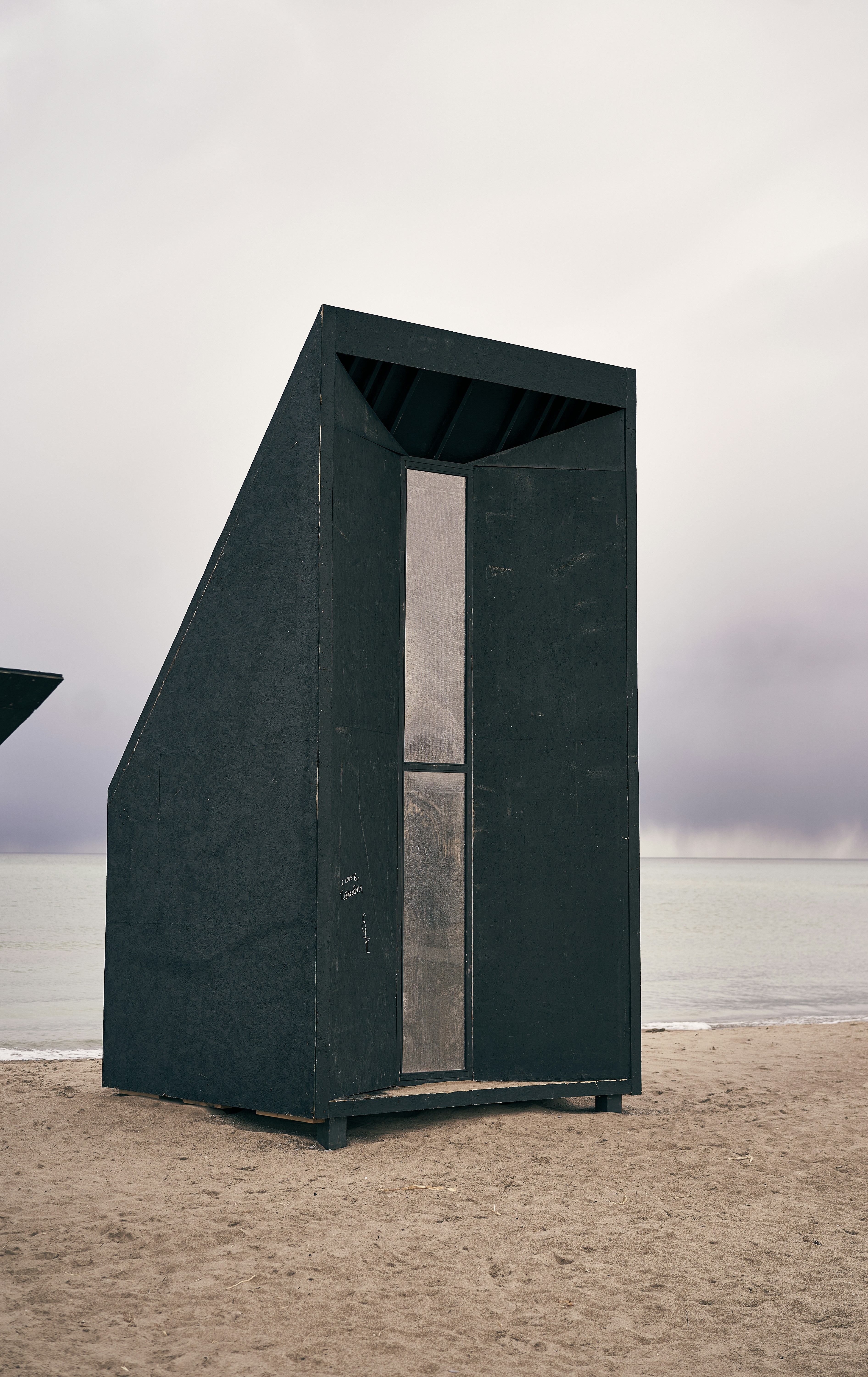 A black outhouse sitting on top of a sandy beach photo – Free Grey ...