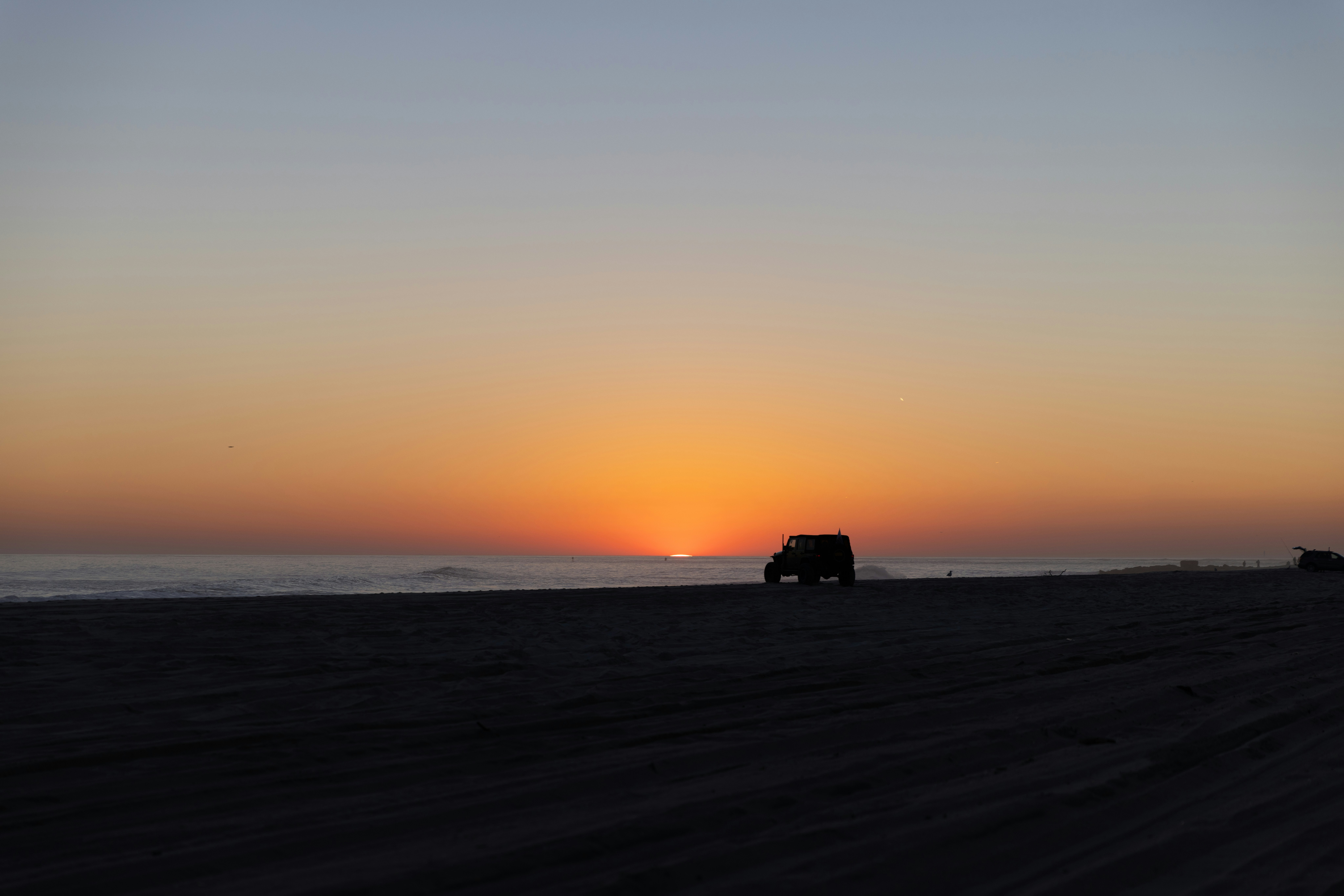 Sunset Silhouette: A Quiet Car Slip by the Shore