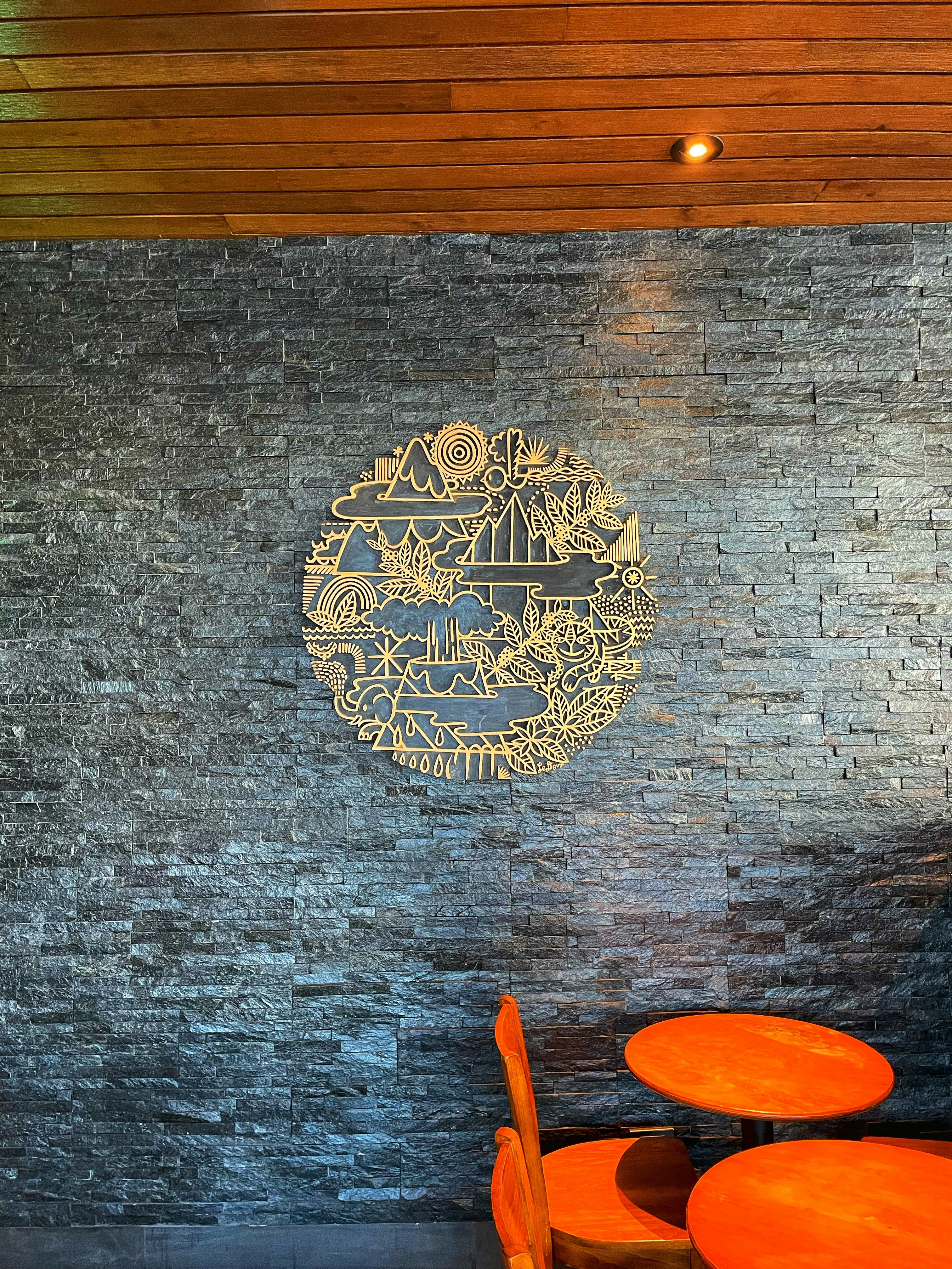 Circular wall mural anchors a cozy cafe corner beneath warm wood and slate