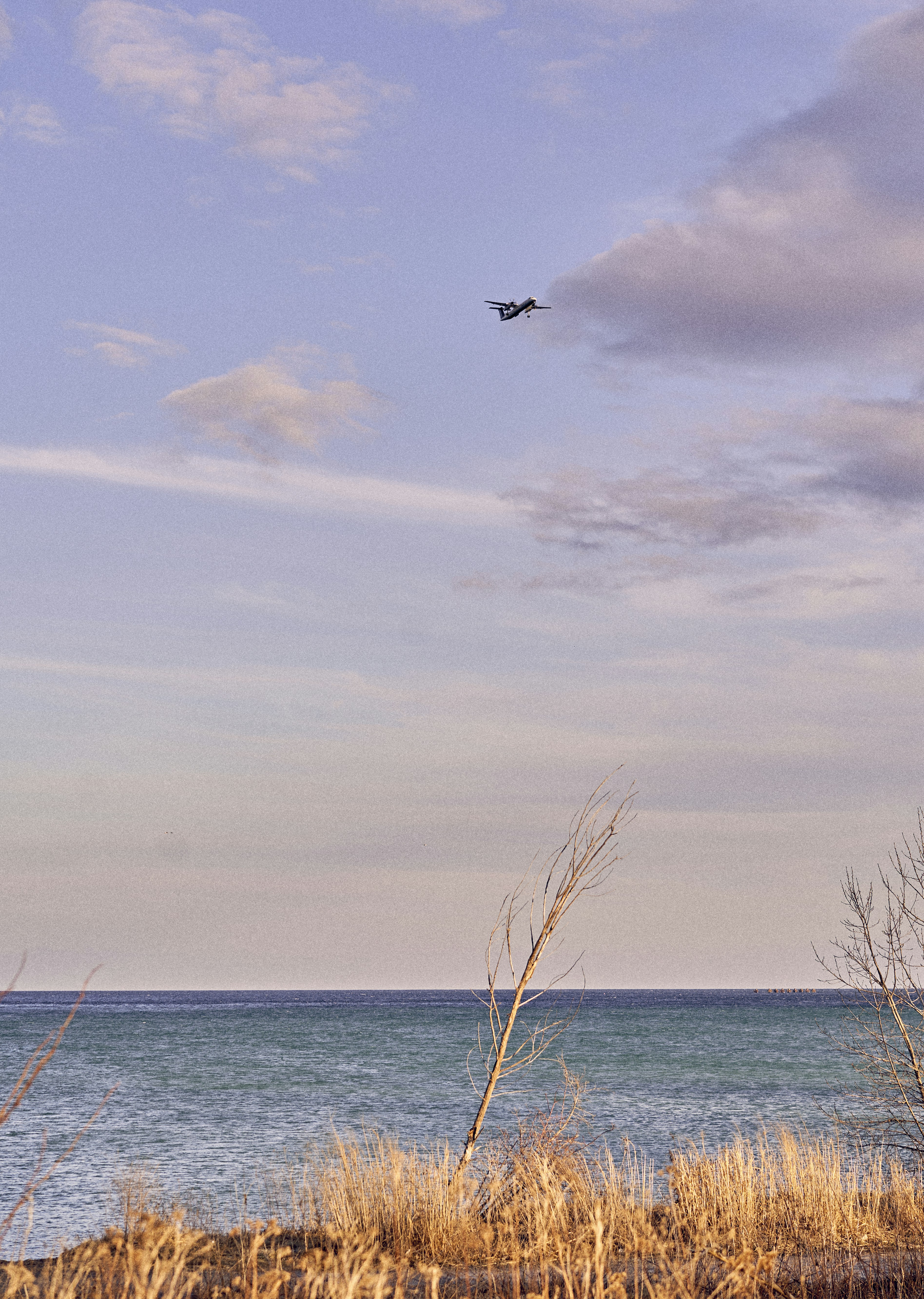Lone Jet Skimming the Quiet Horizon Over a Coastal Dusk