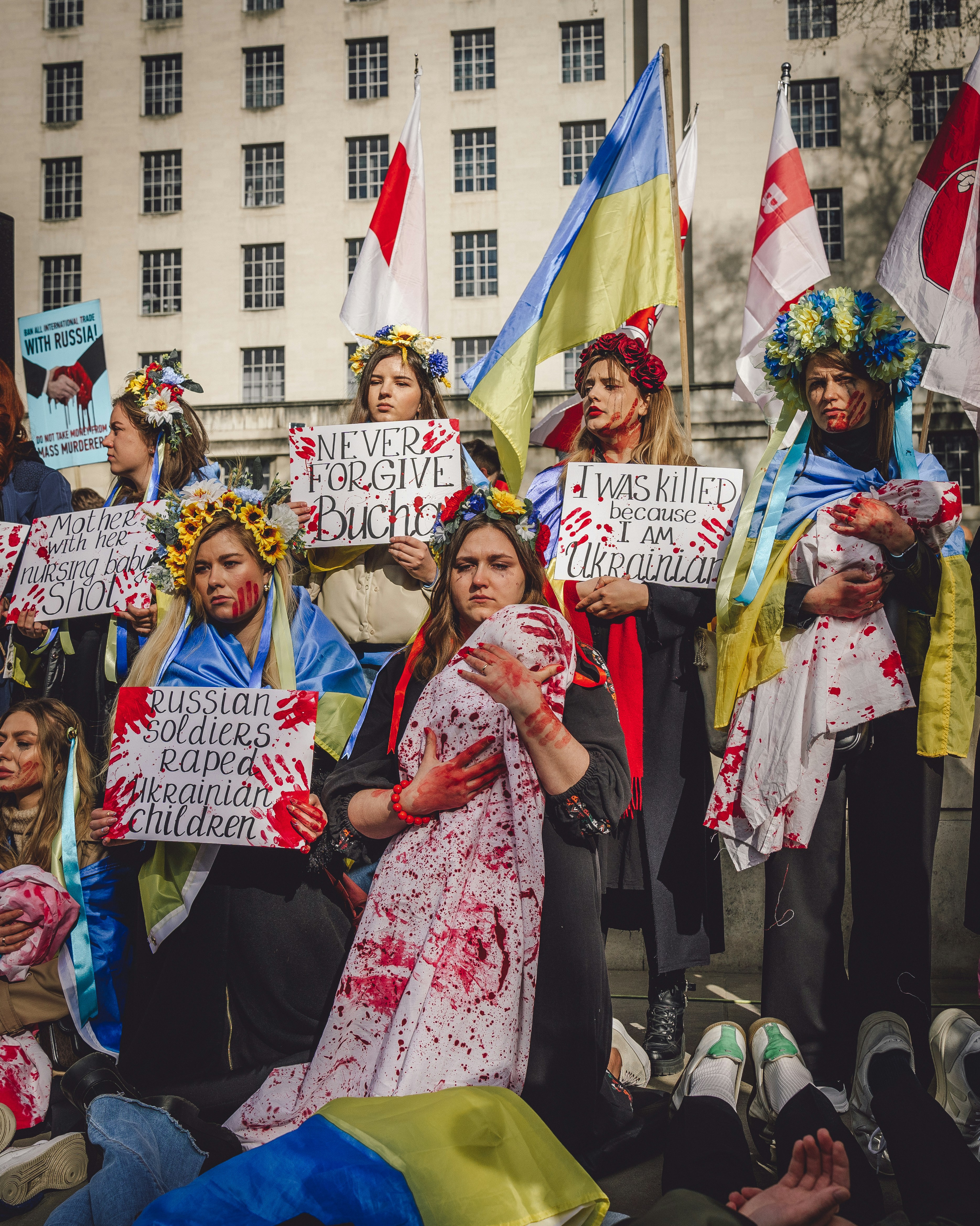Activists draped in Ukrainian flags hold signs demanding justice for victims of war atrocities, showcasing solidarity and the fight for human rights.