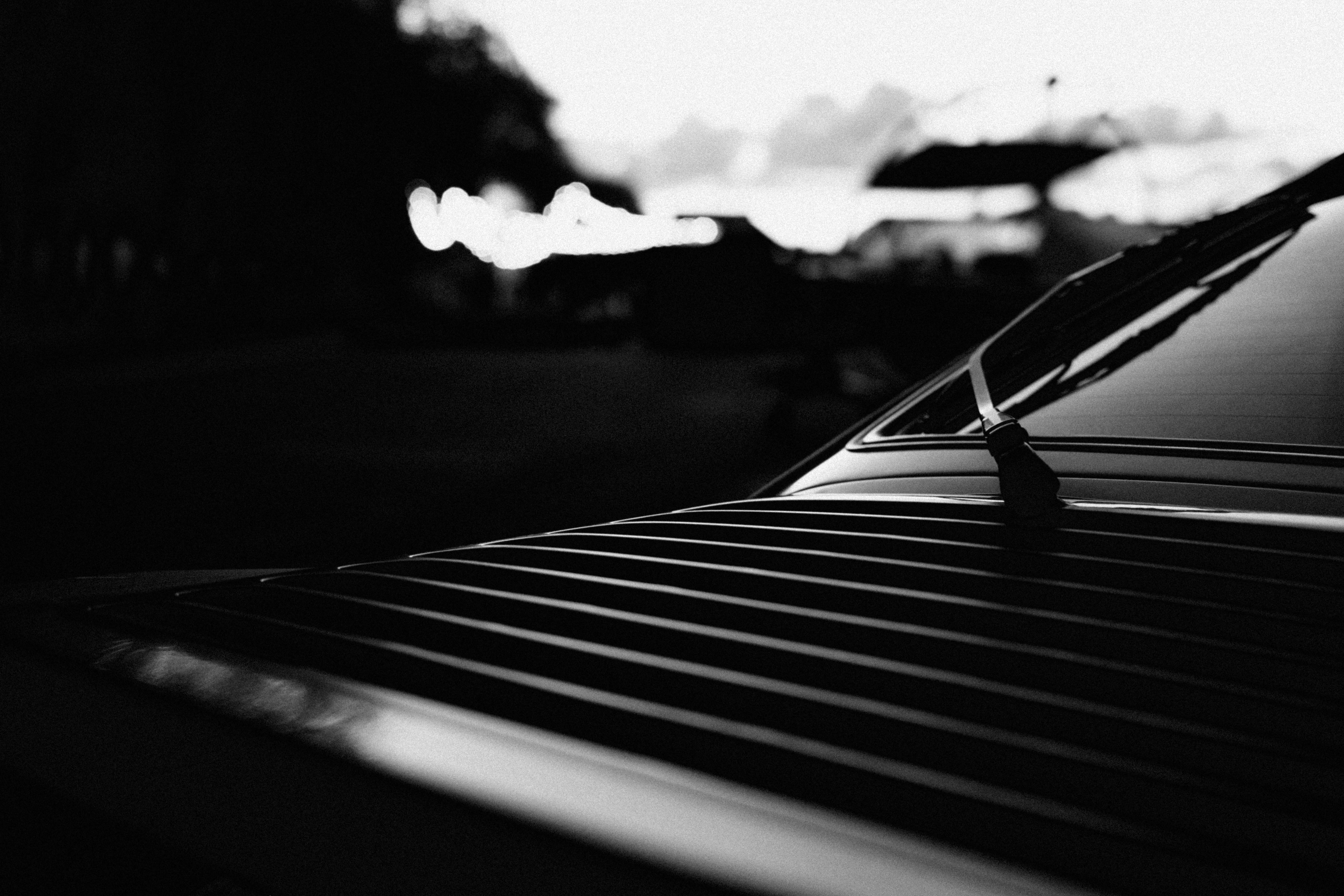 Close-up view of a vintage car's sleek lines and reflections in monochrome. The focus on the car's surface highlights its classic design.