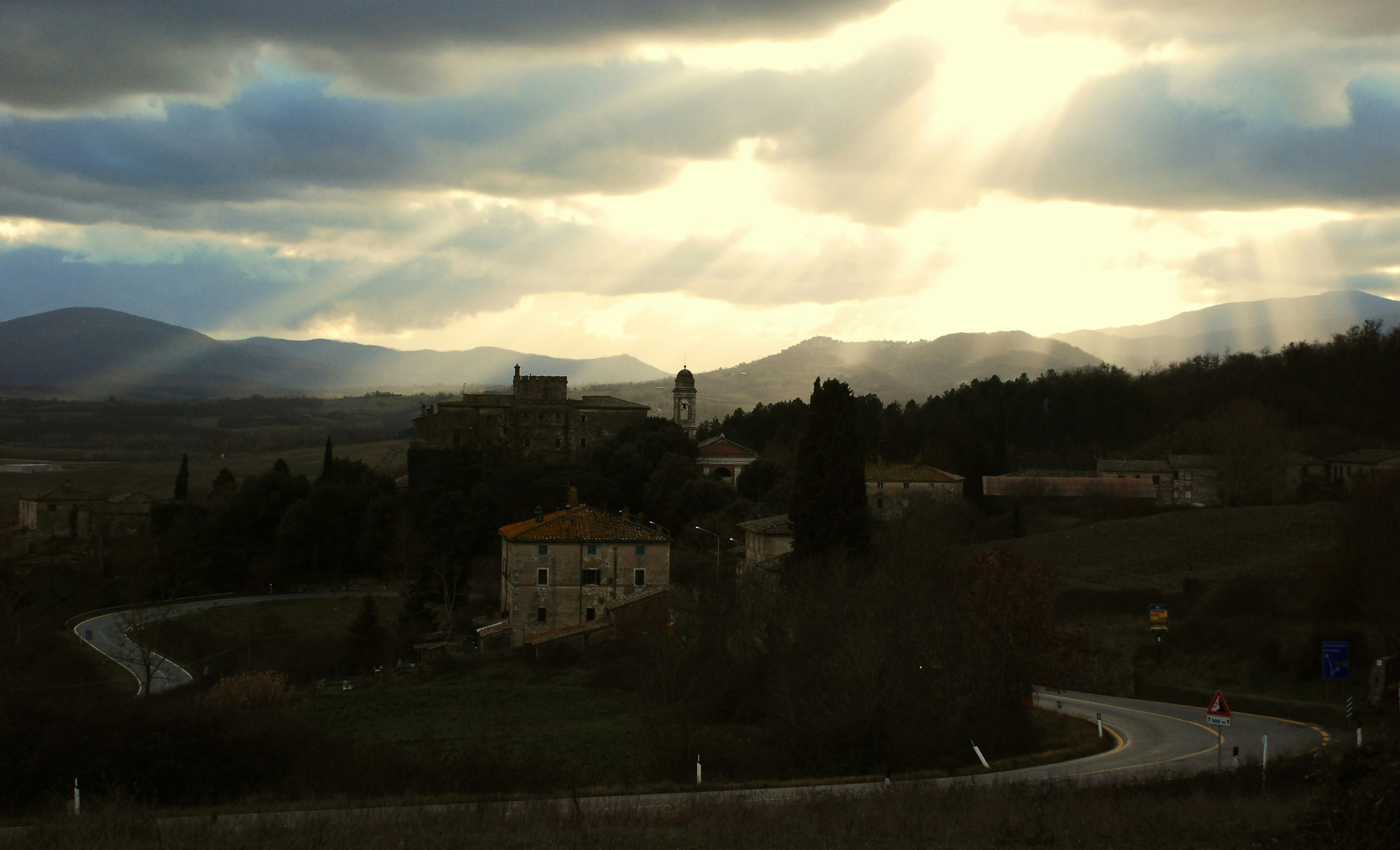 the sun shines through the clouds over a road