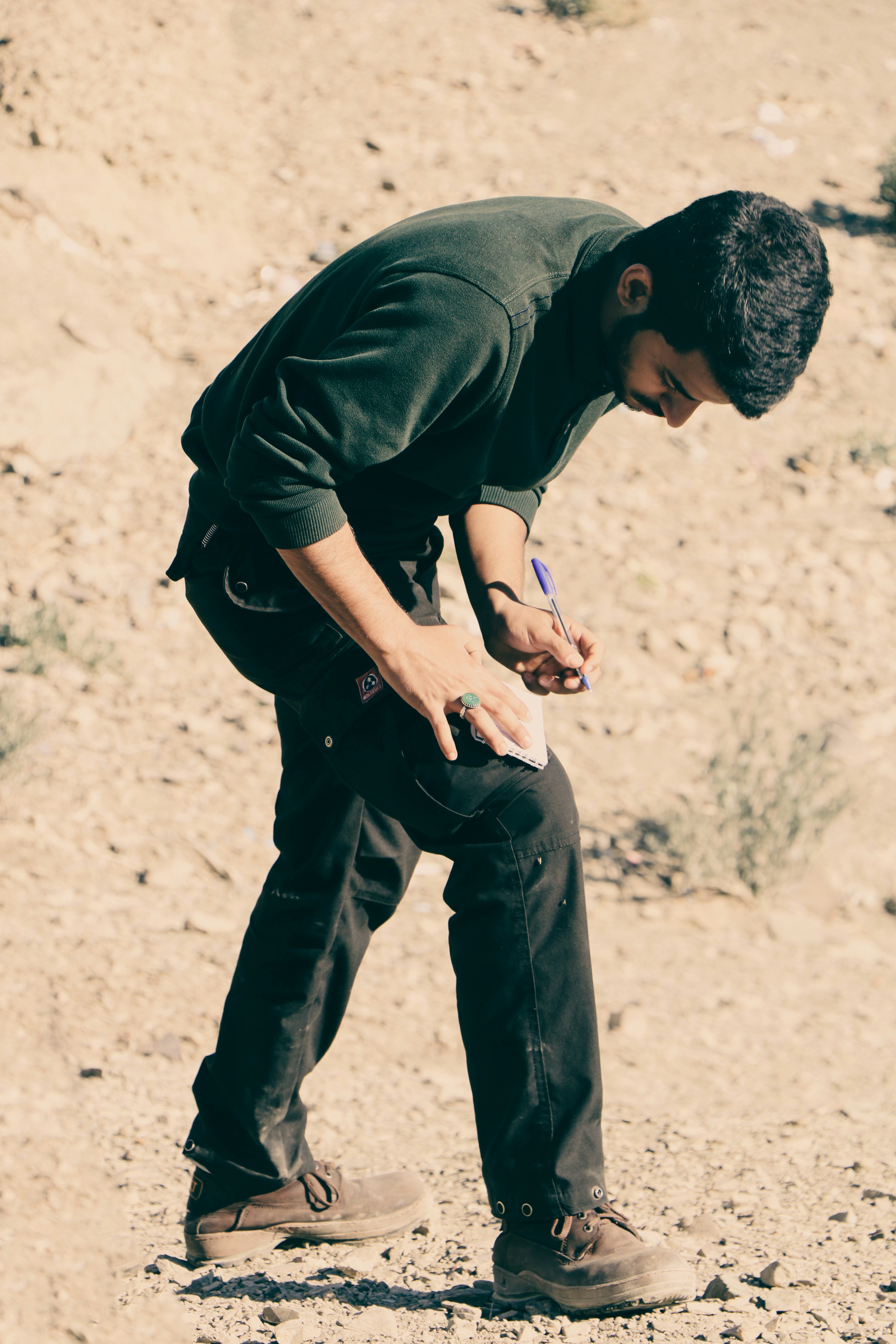 A man standing in the dirt writing on a piece of paper photo – Free ...