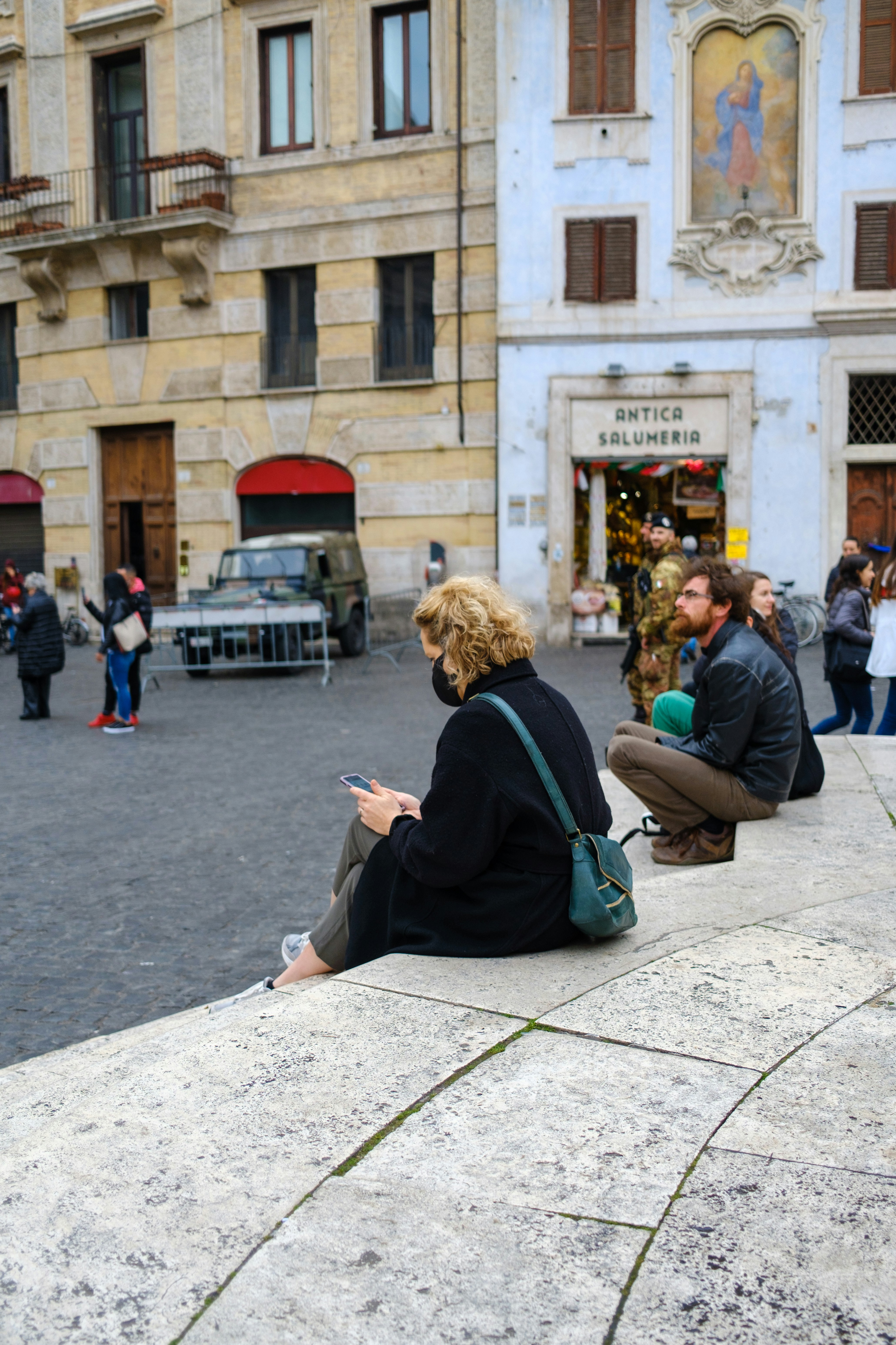 Piazza Quiet: A Woman in Black Checks Her Phone as City Life Flows