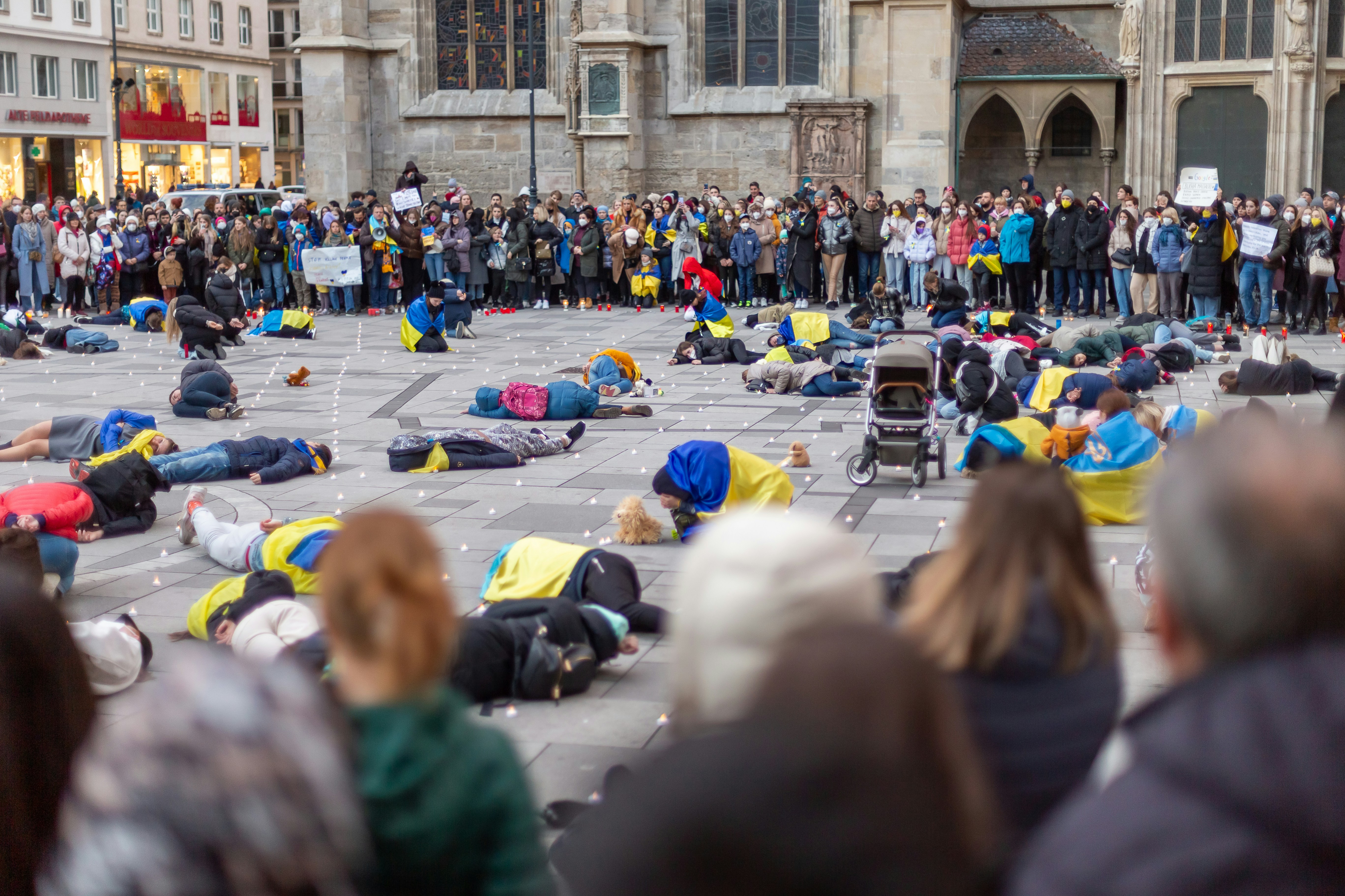 A crowd of people standing around a group of people laying on the ...