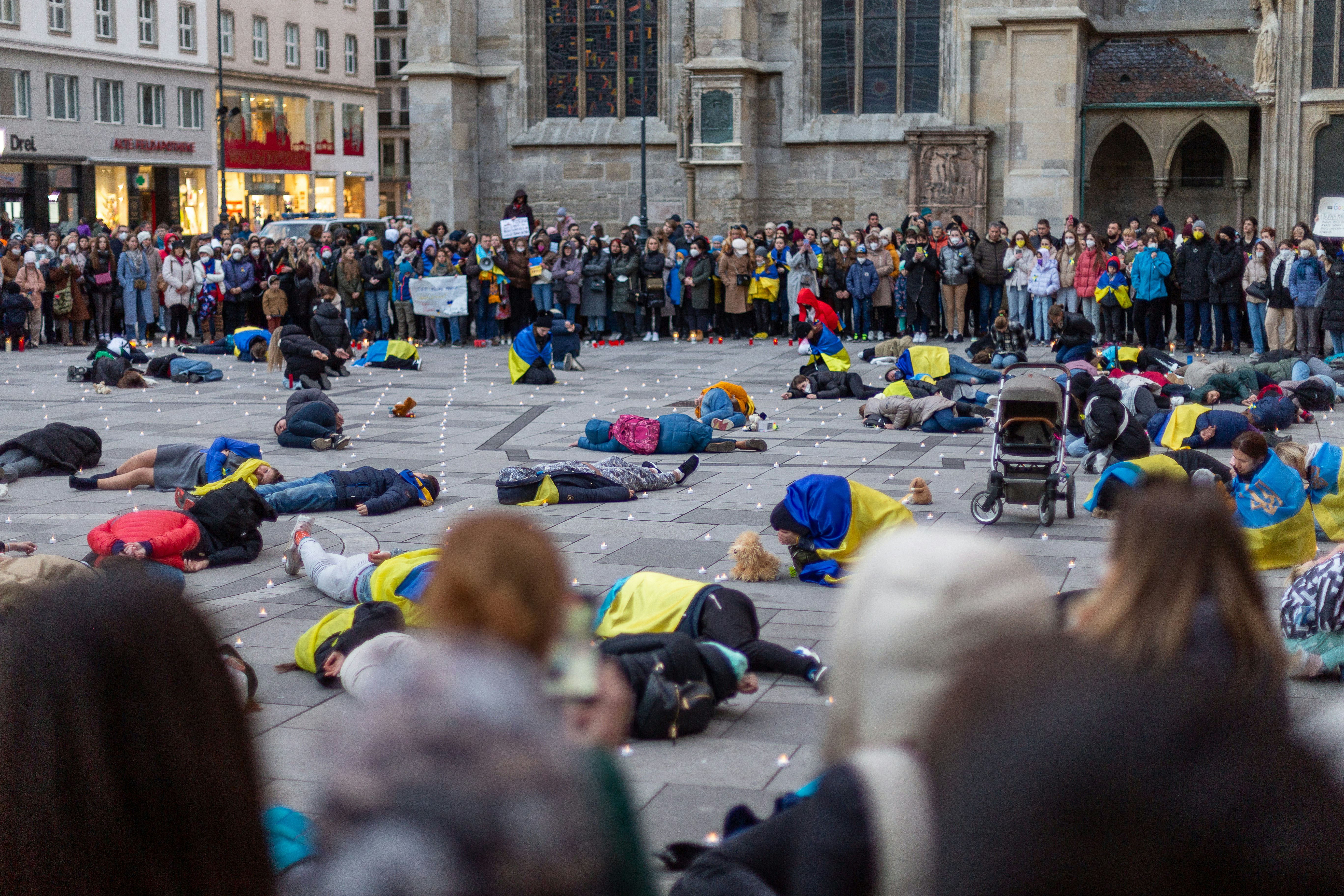 A crowd of people standing around a group of people laying on the ...
