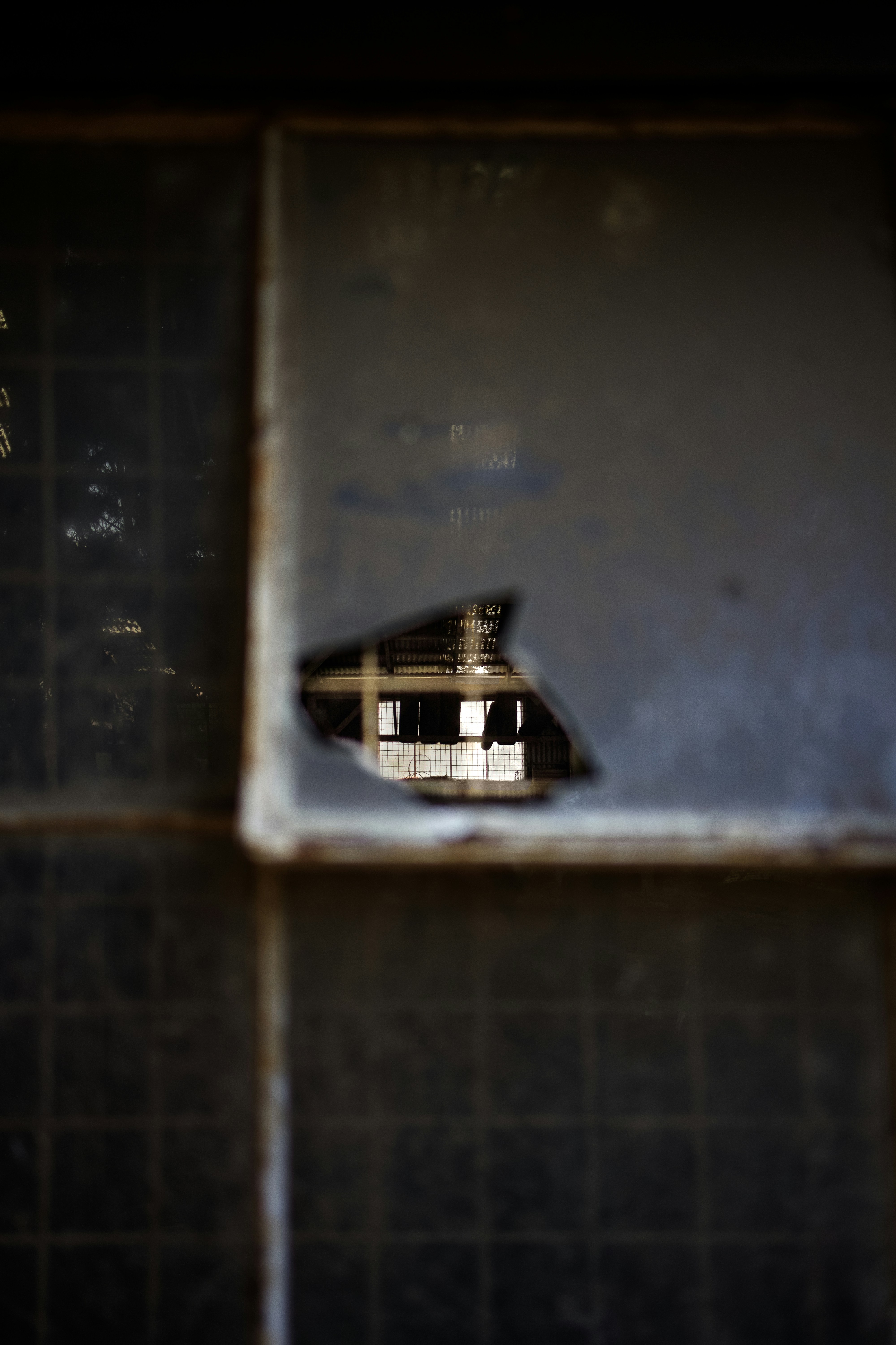 Through a Cracked Panel: Light Framing a Rusted Grid