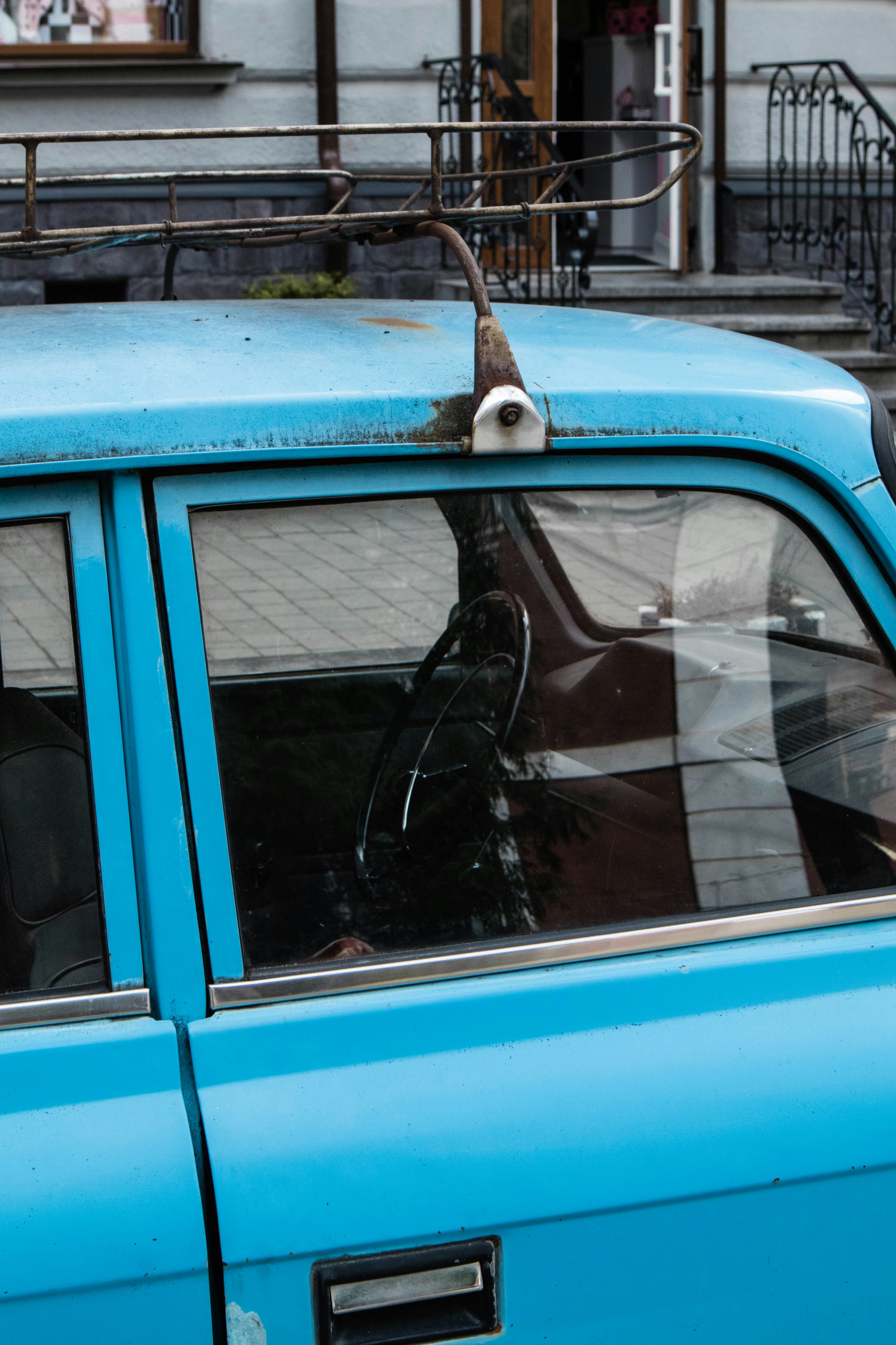 Turquoise Vintage Car: Rusted Roof Rack and Quiet Street Reflections