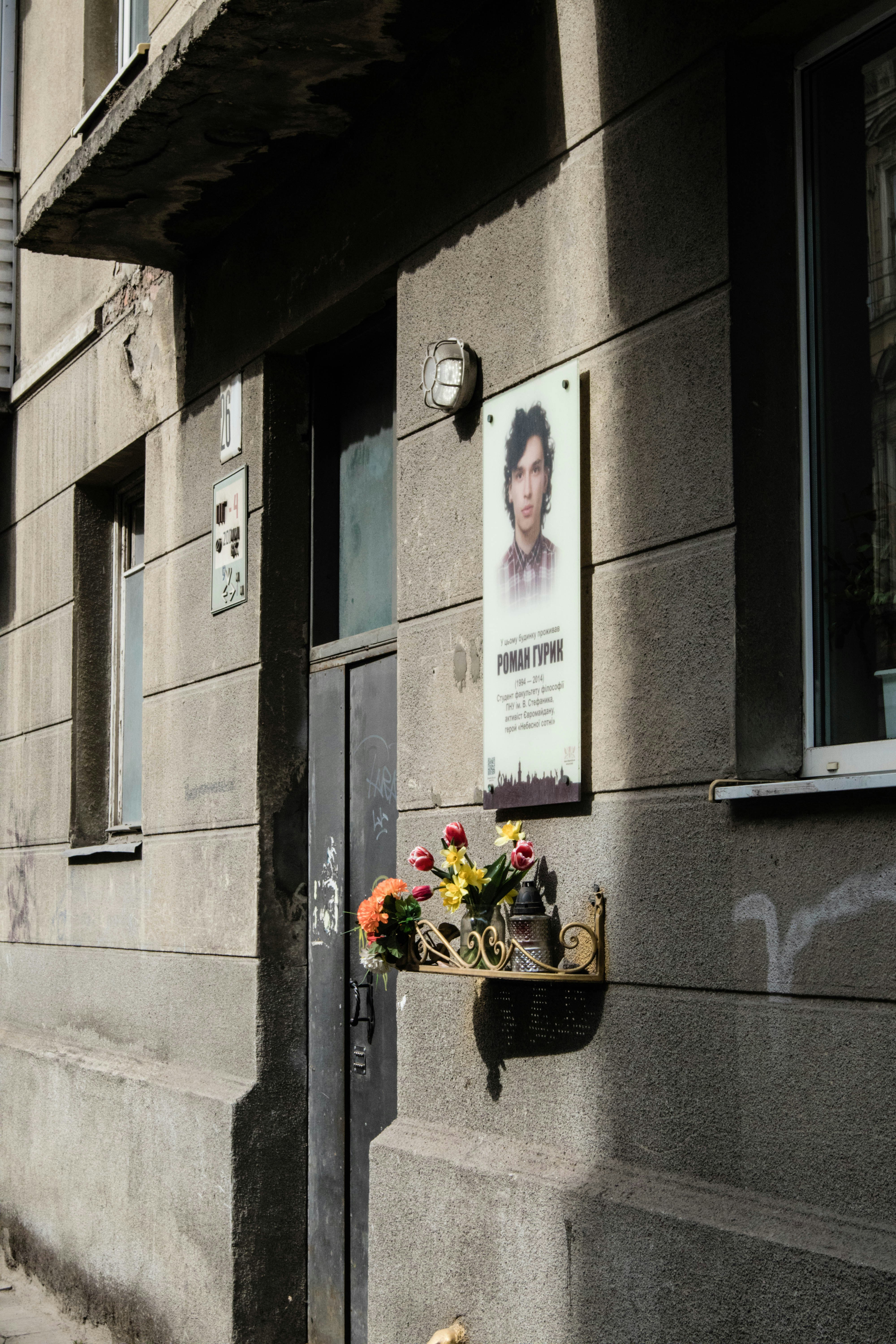 Portrait Plaque Framed by a Floral Tribute on a Weathered City Facade