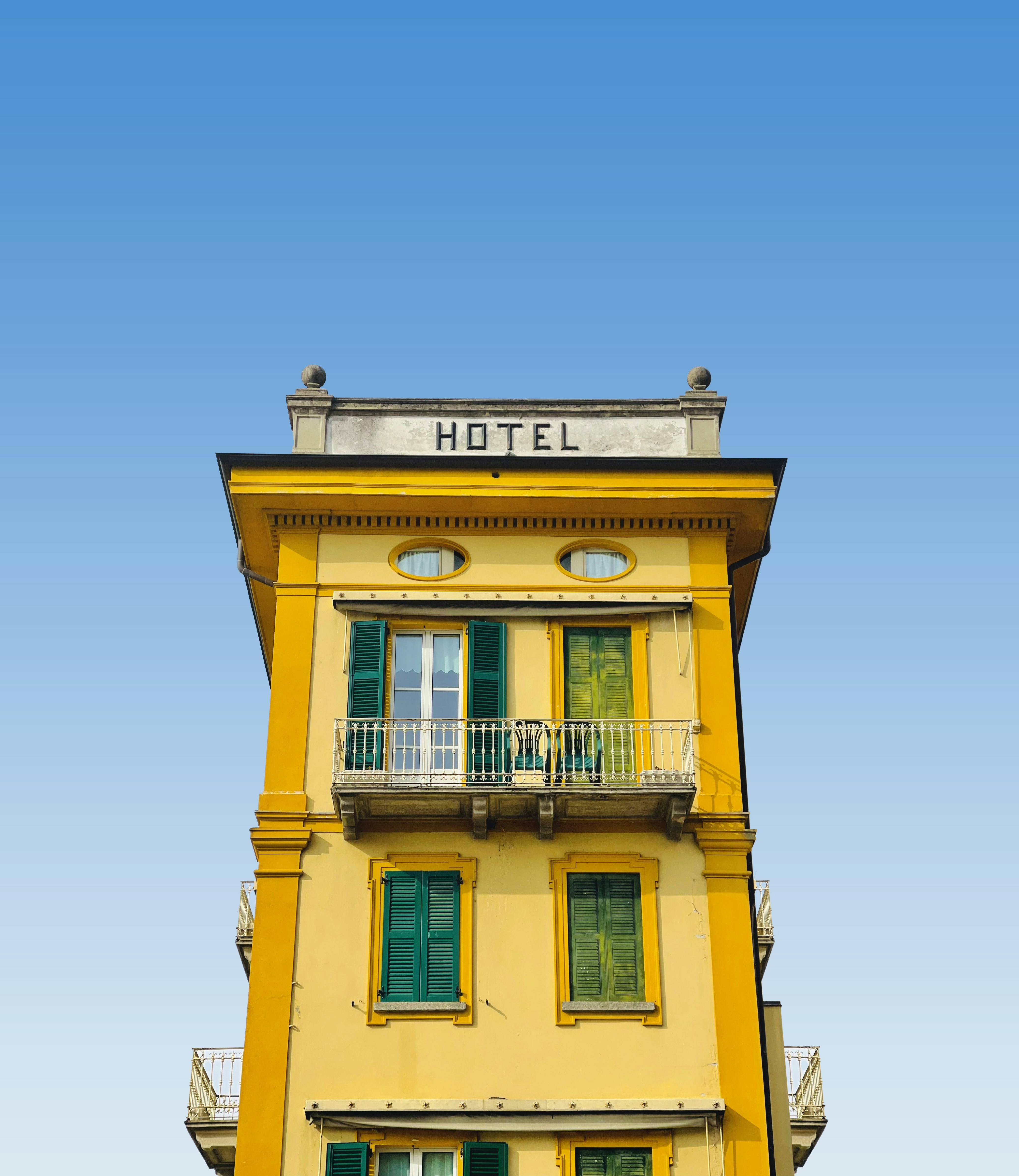 A tall yellow building with a balcony and balconies photo – Free ...