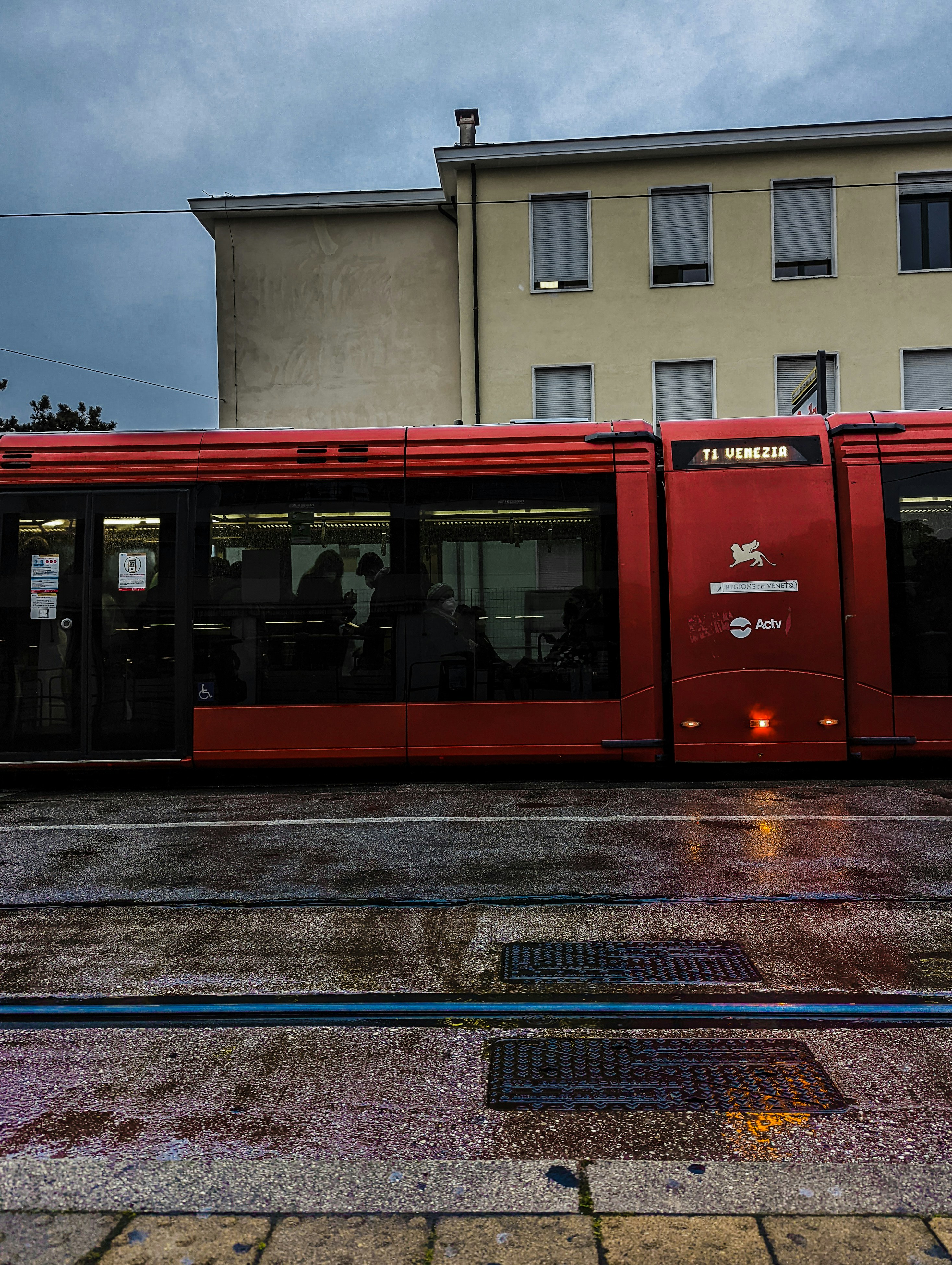 a red bus driving down a street next to a tall building