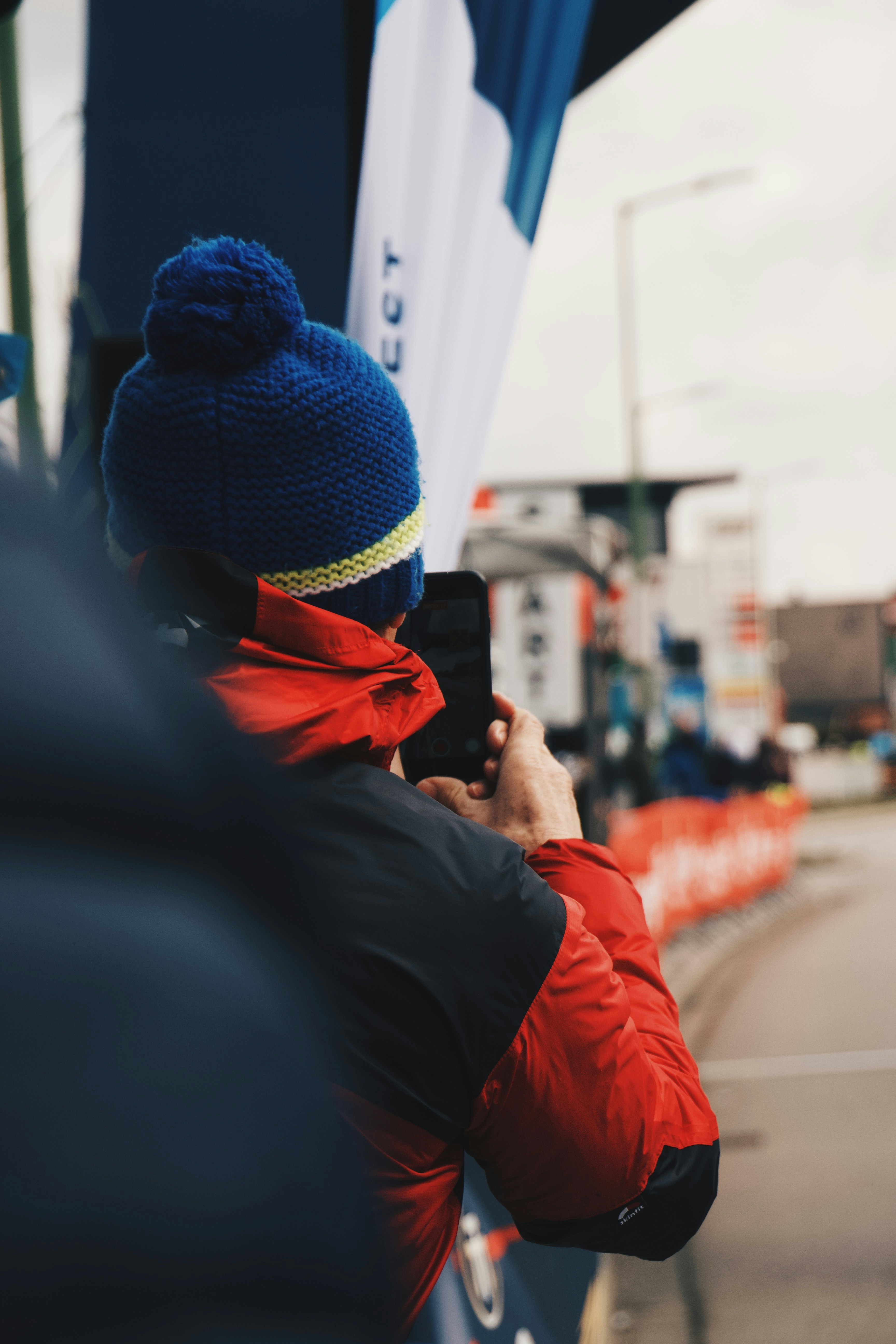 Blue Beanie Edge: A Street Spectator Framing the Race Moment