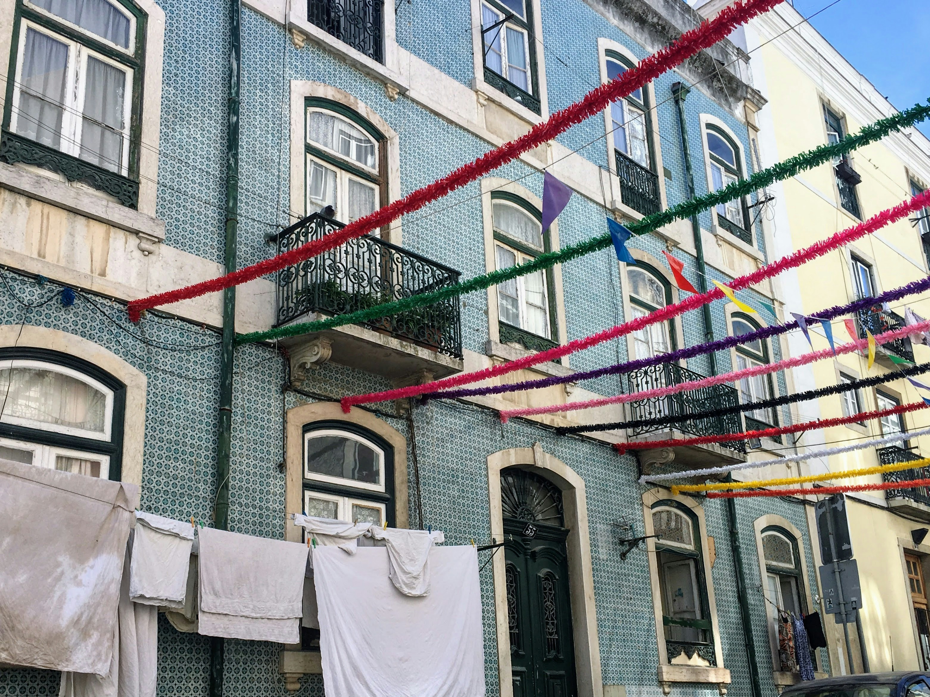 Tiles and Tinsel: A Colorful Street Framed by Laundry and Festooned Lines