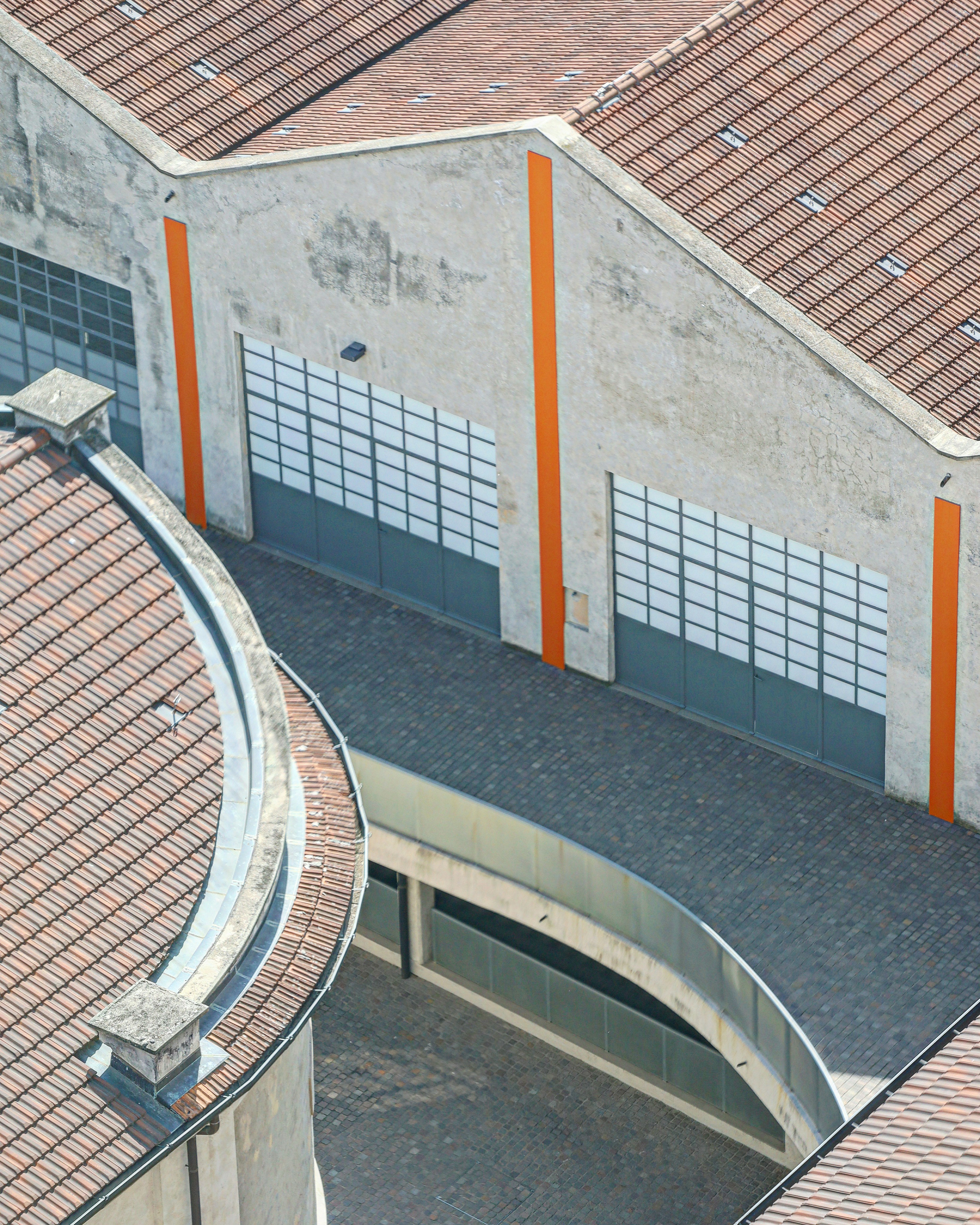 Aerial view of industrial buildings showcasing a blend of angular structures and circular elements, highlighted by vibrant orange accents.