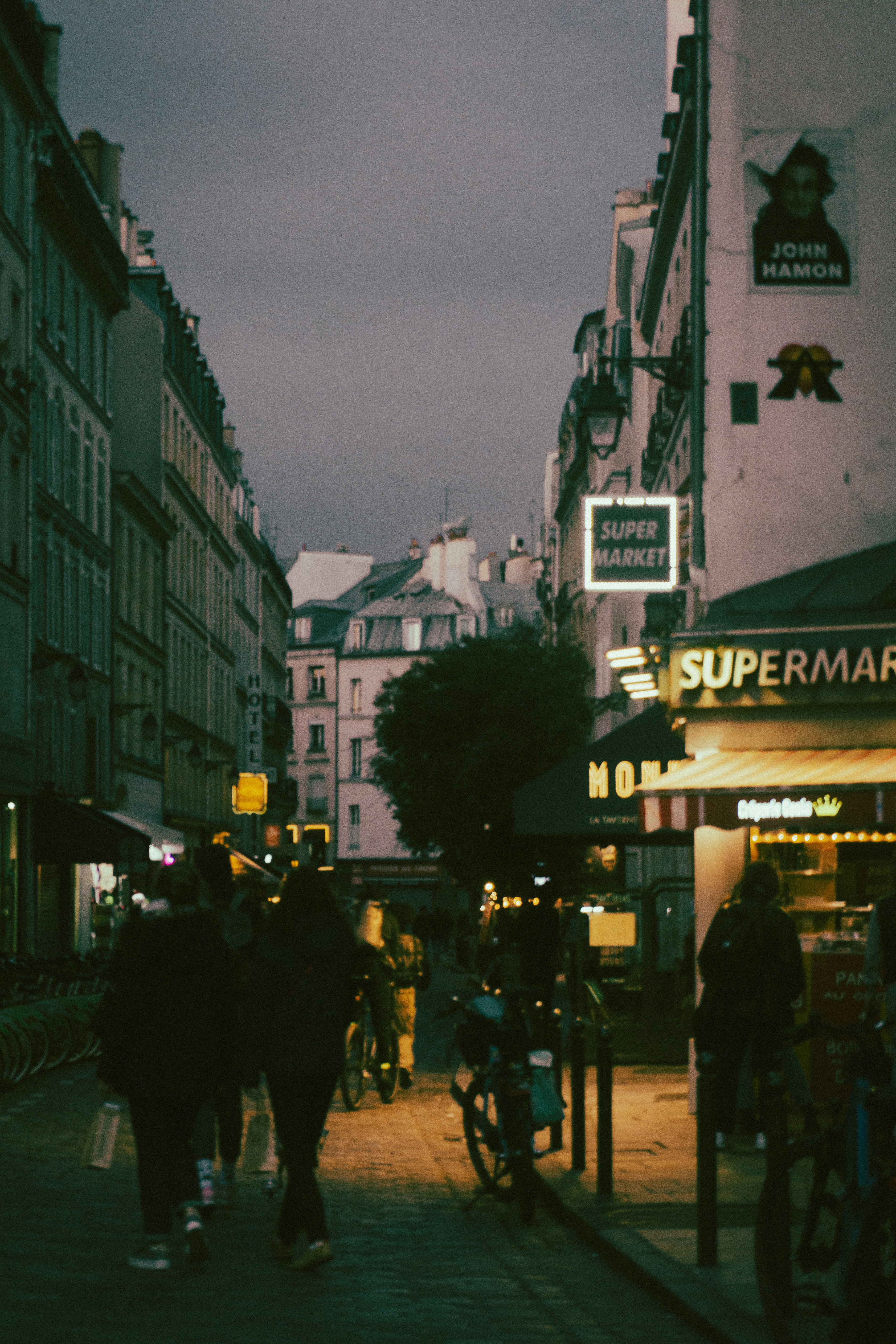 Neon Market Glow Seeping Through a Narrow European Street at Dusk