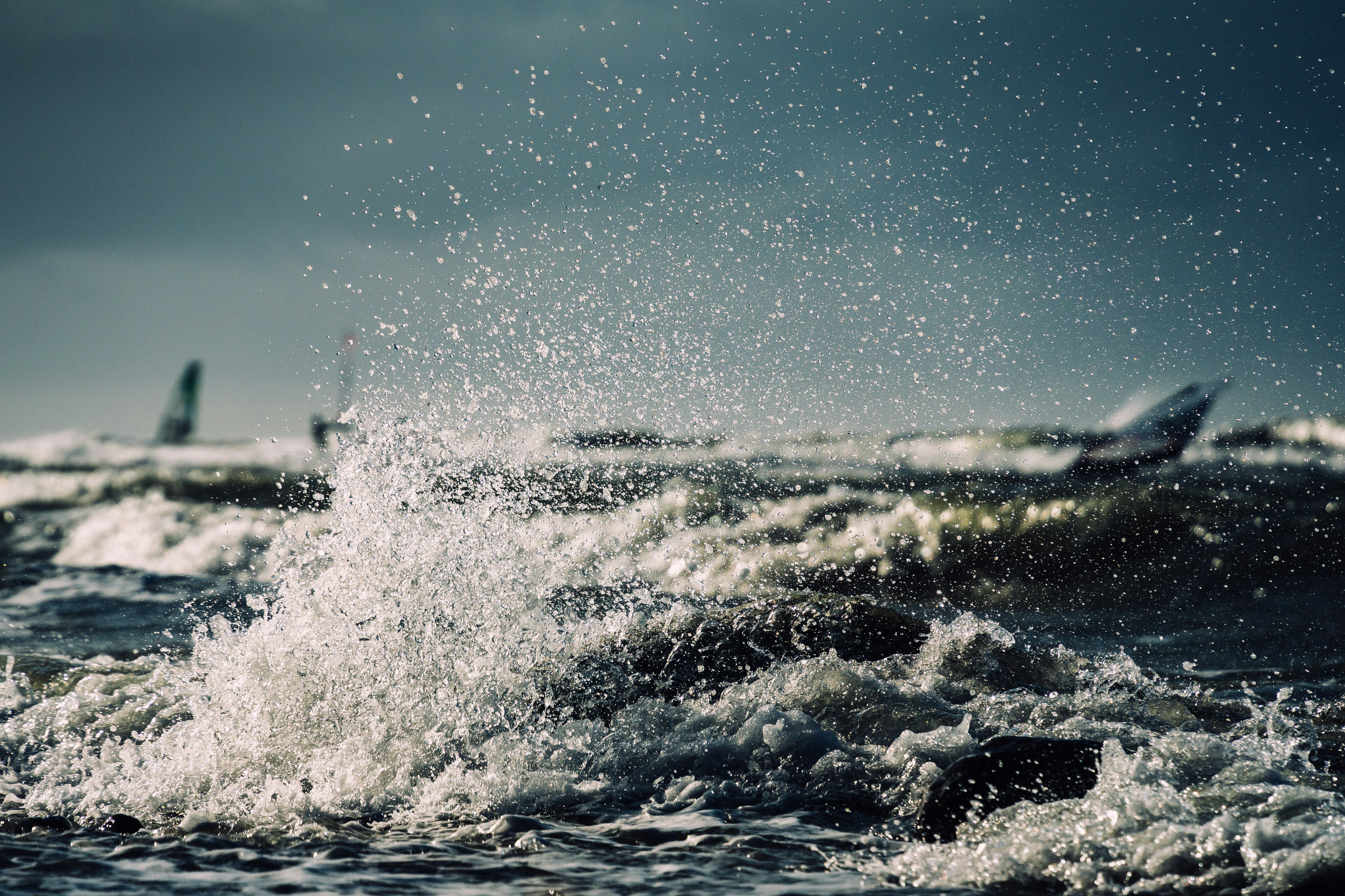 Ocean waves crashing with force under a dark, turbulent sky.